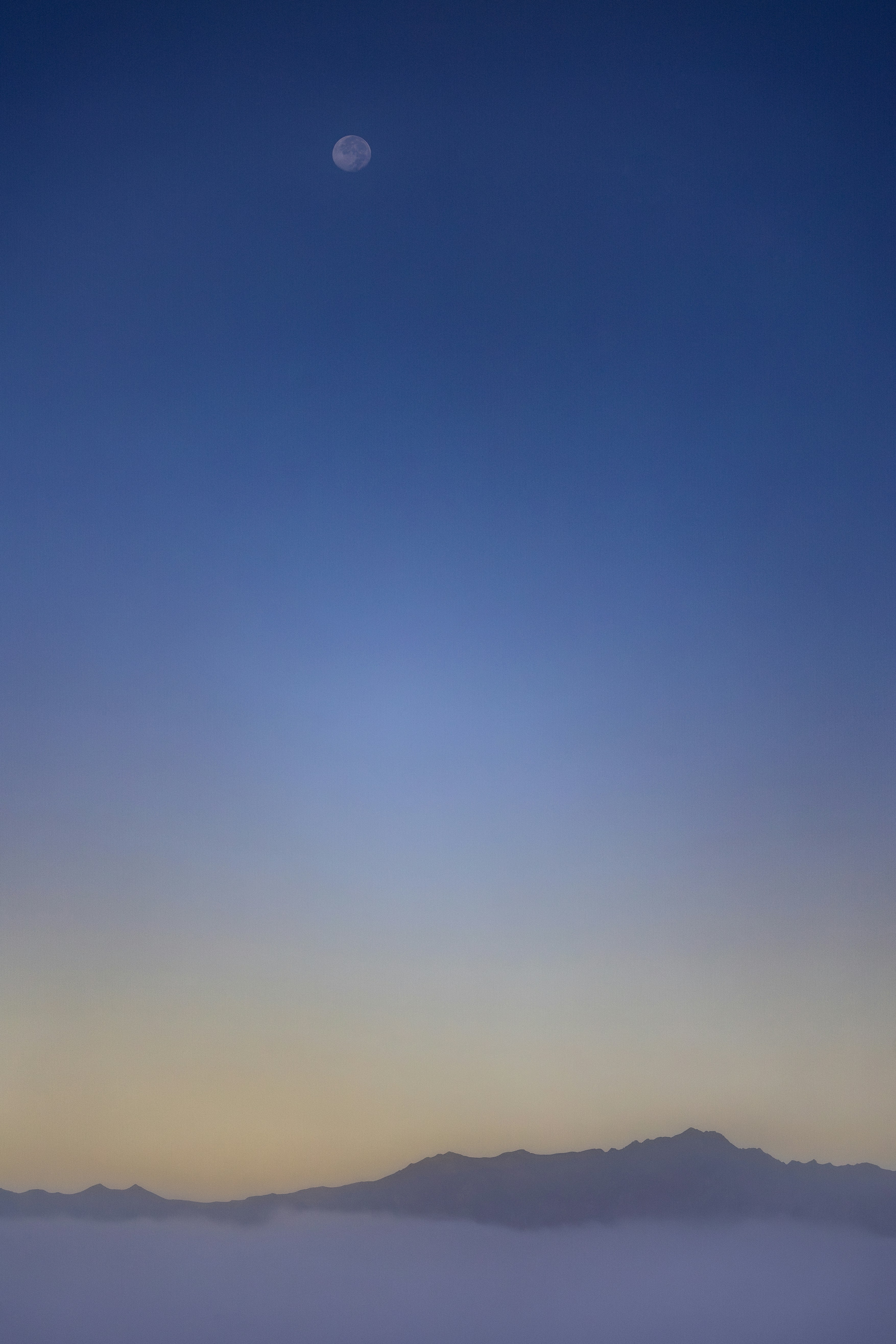Moon over a peaceful desert horizon at blue hour