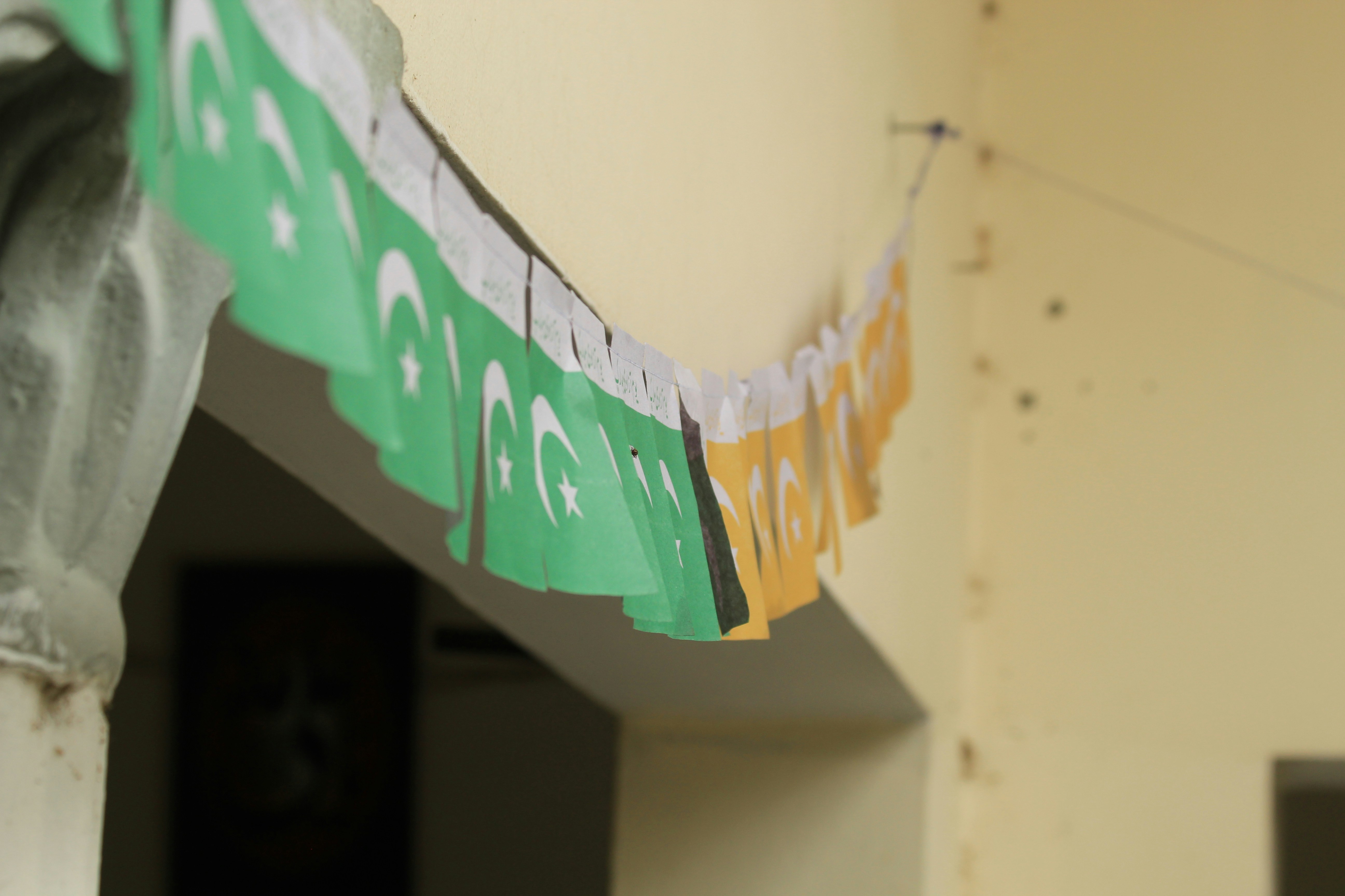 Colorful pennants flutter over a doorway, fading into a muted courtyard
