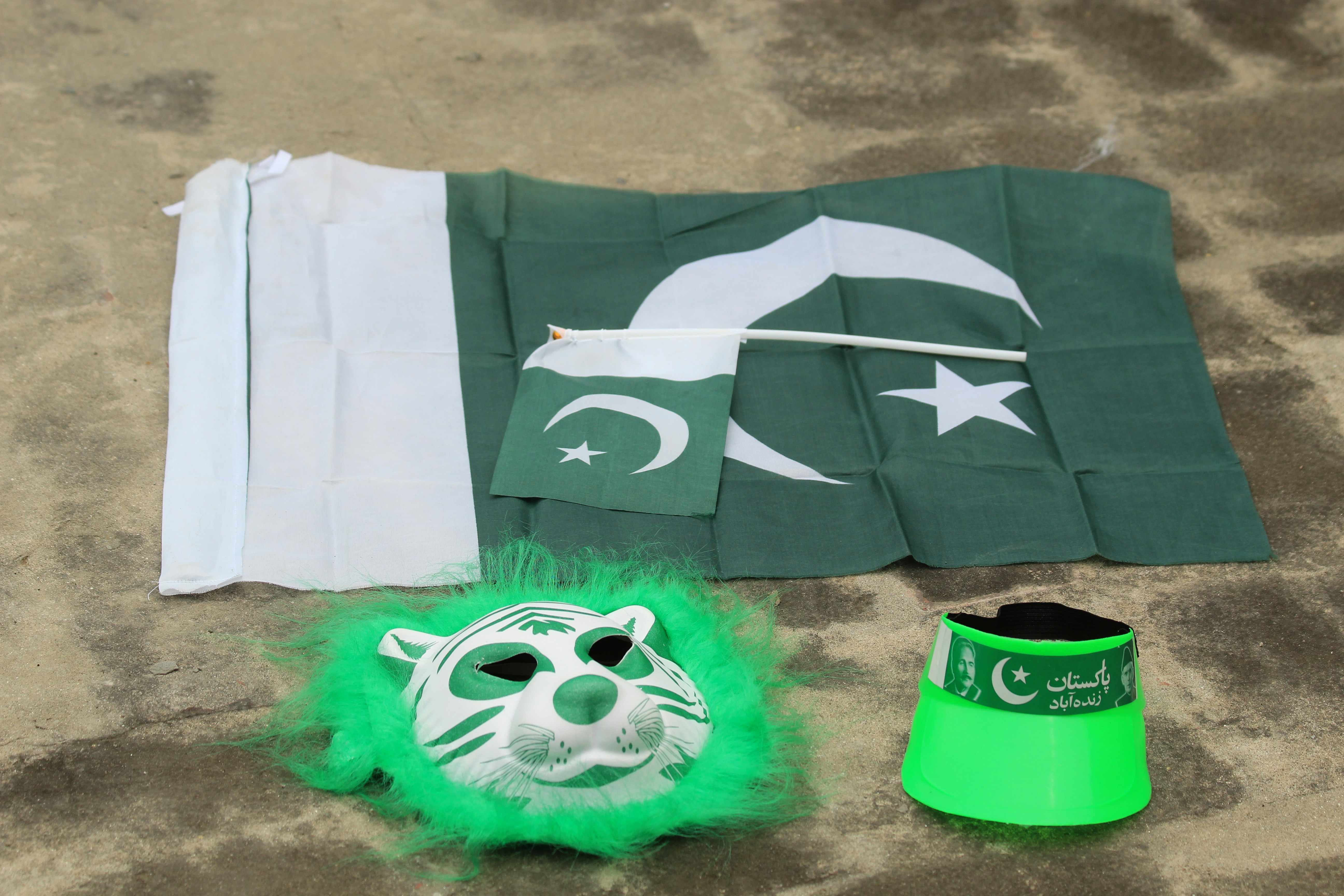Green Mascot Echoes with Flag Fragments on a Concrete Stage