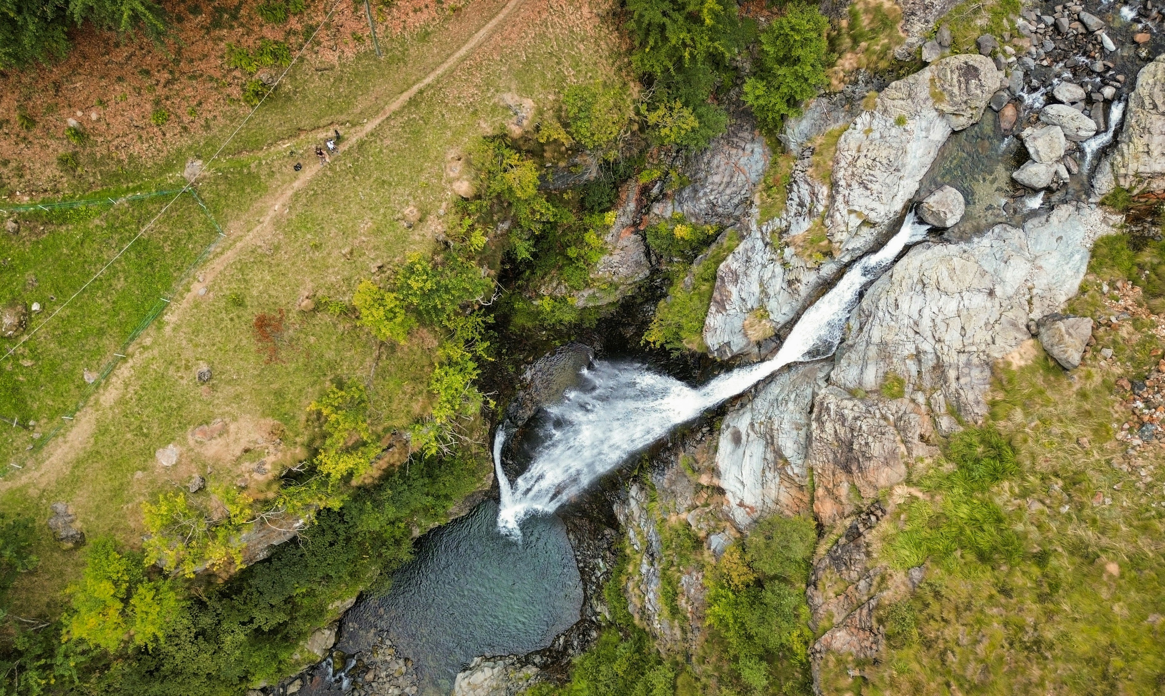 Aerial Cascade: Waterfall Slicing Through Rock and Green