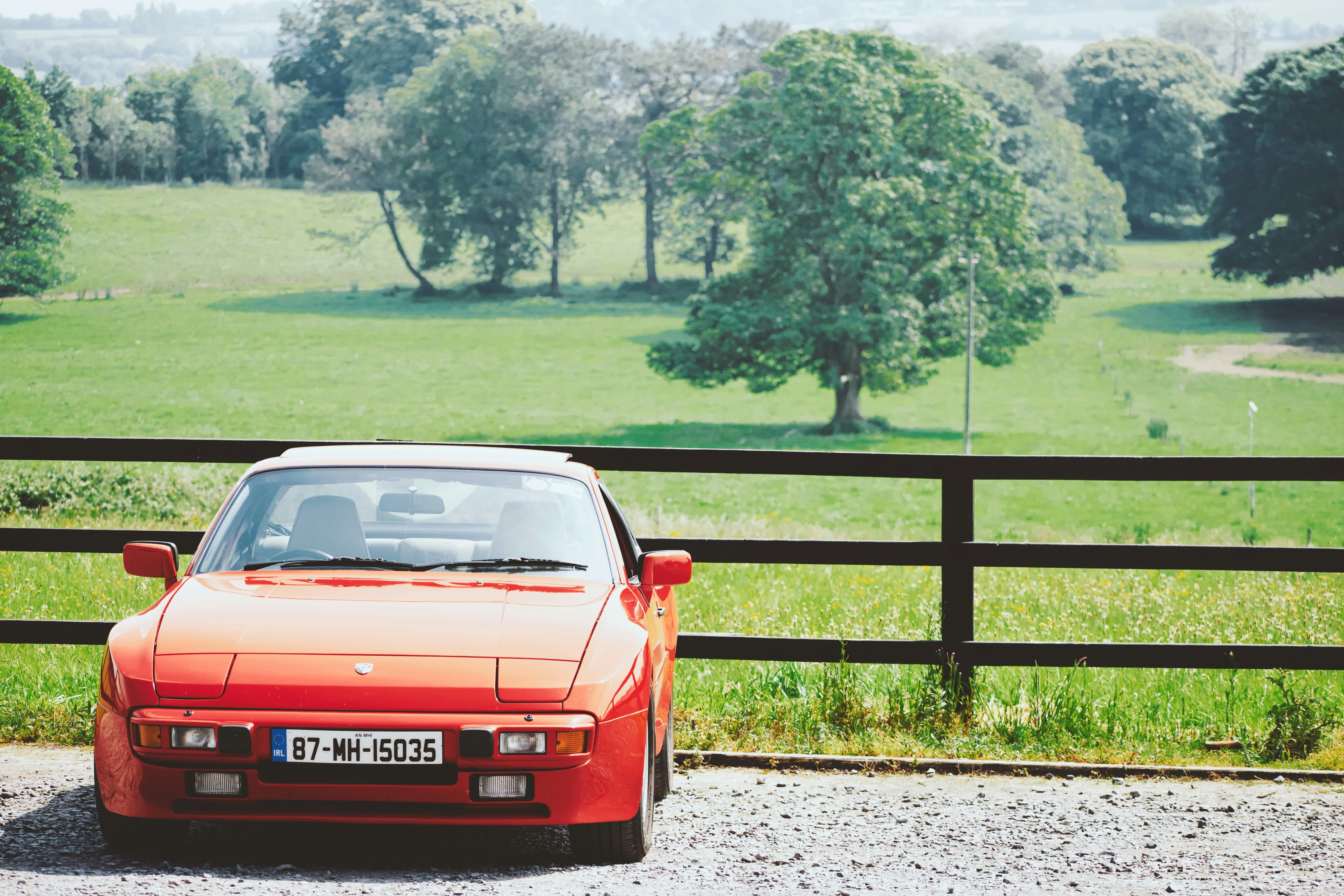 Crimson Classic by the Fence: A Red Cabrio Anchored in Open Pasture