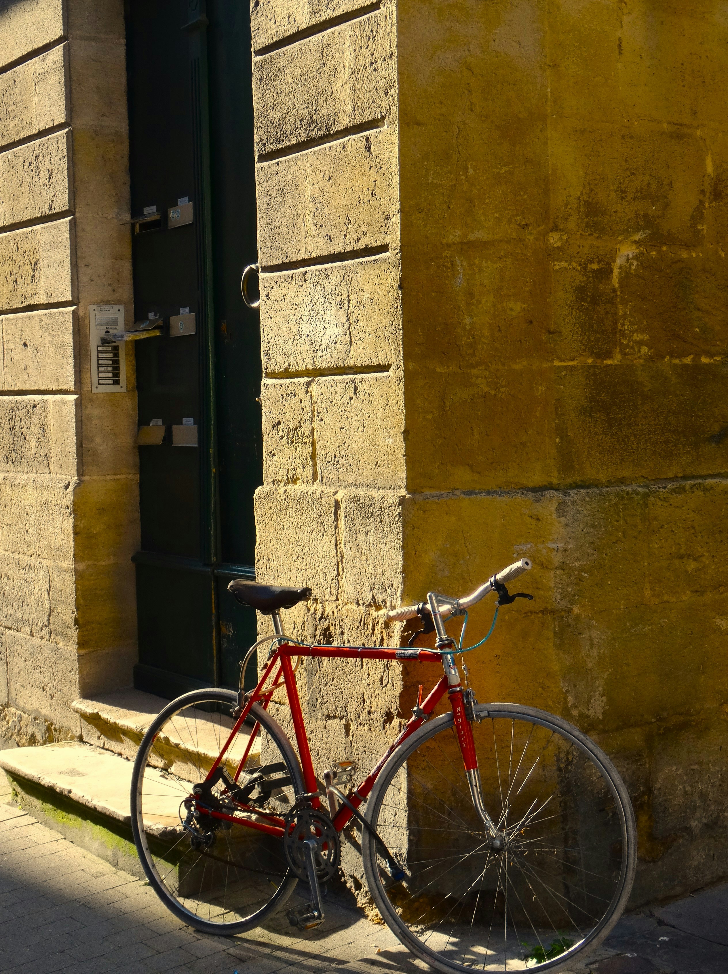 Red Bicycle by a Sunlit Stone Wall