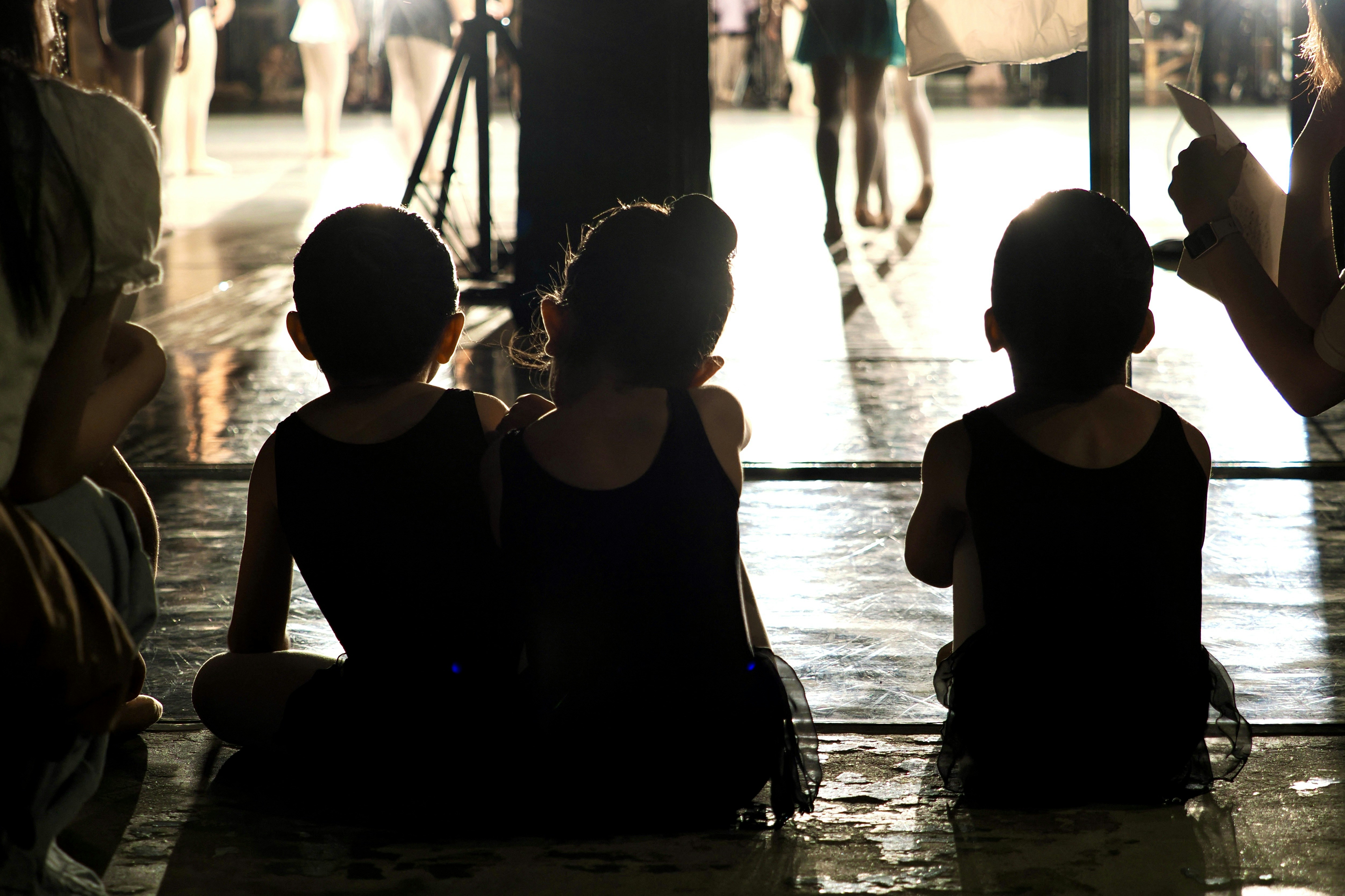 Backlit silhouettes of young dancers awaiting their cue