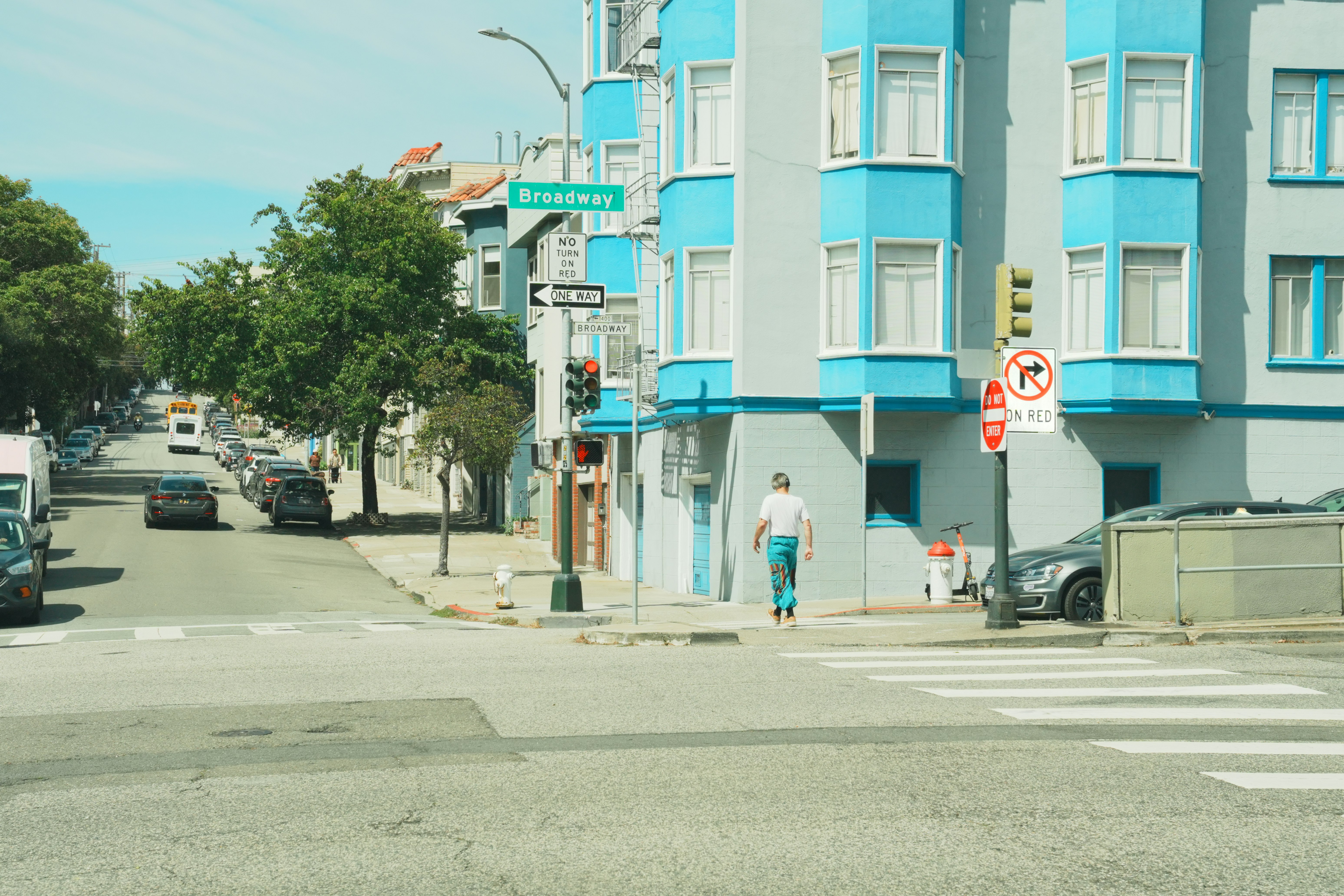 Crosswalk at Broadway: A Sunlit Street Scene with a Colorful Corner Building