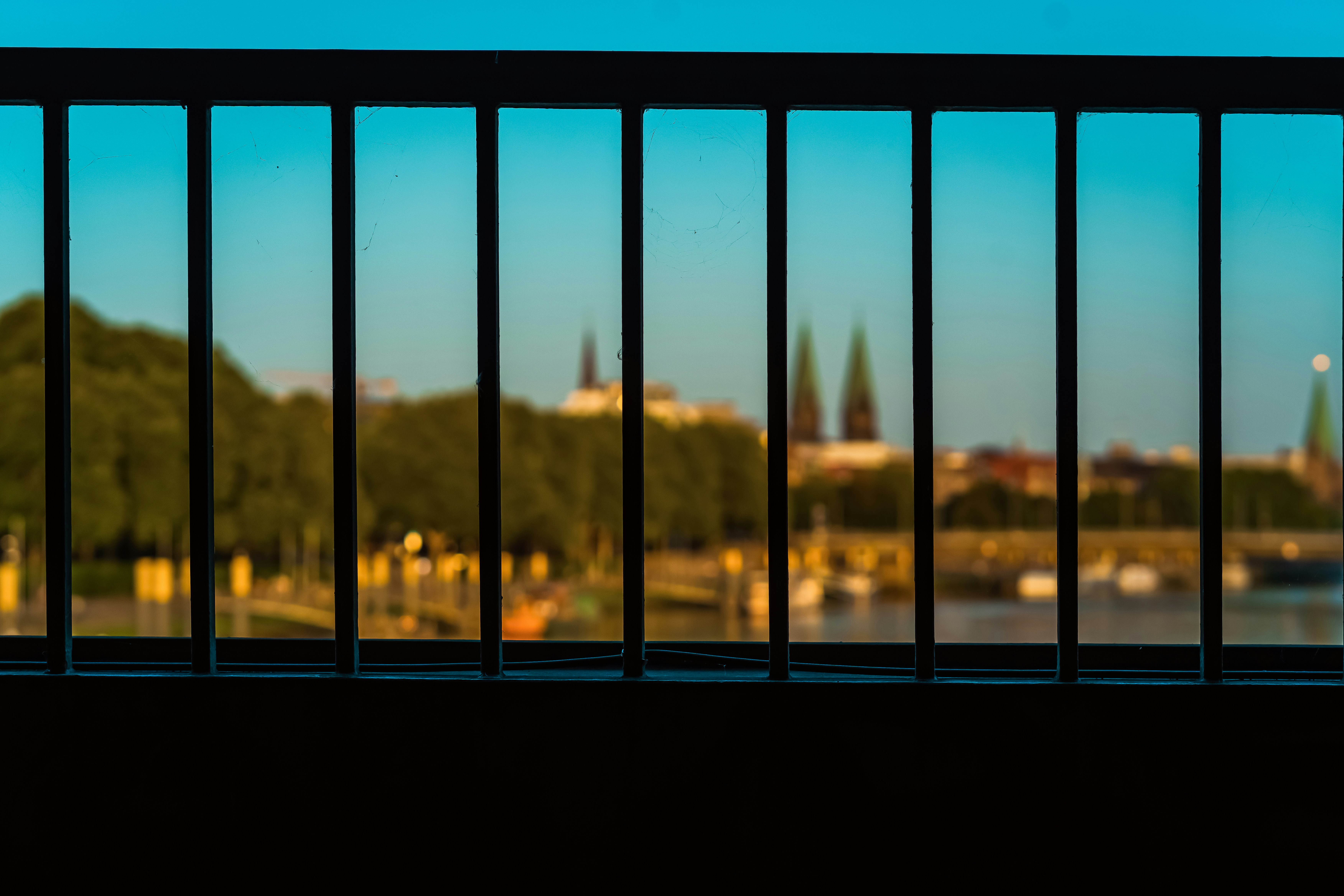 Bars Across the Water: A Quiet Cityscape through a Railing