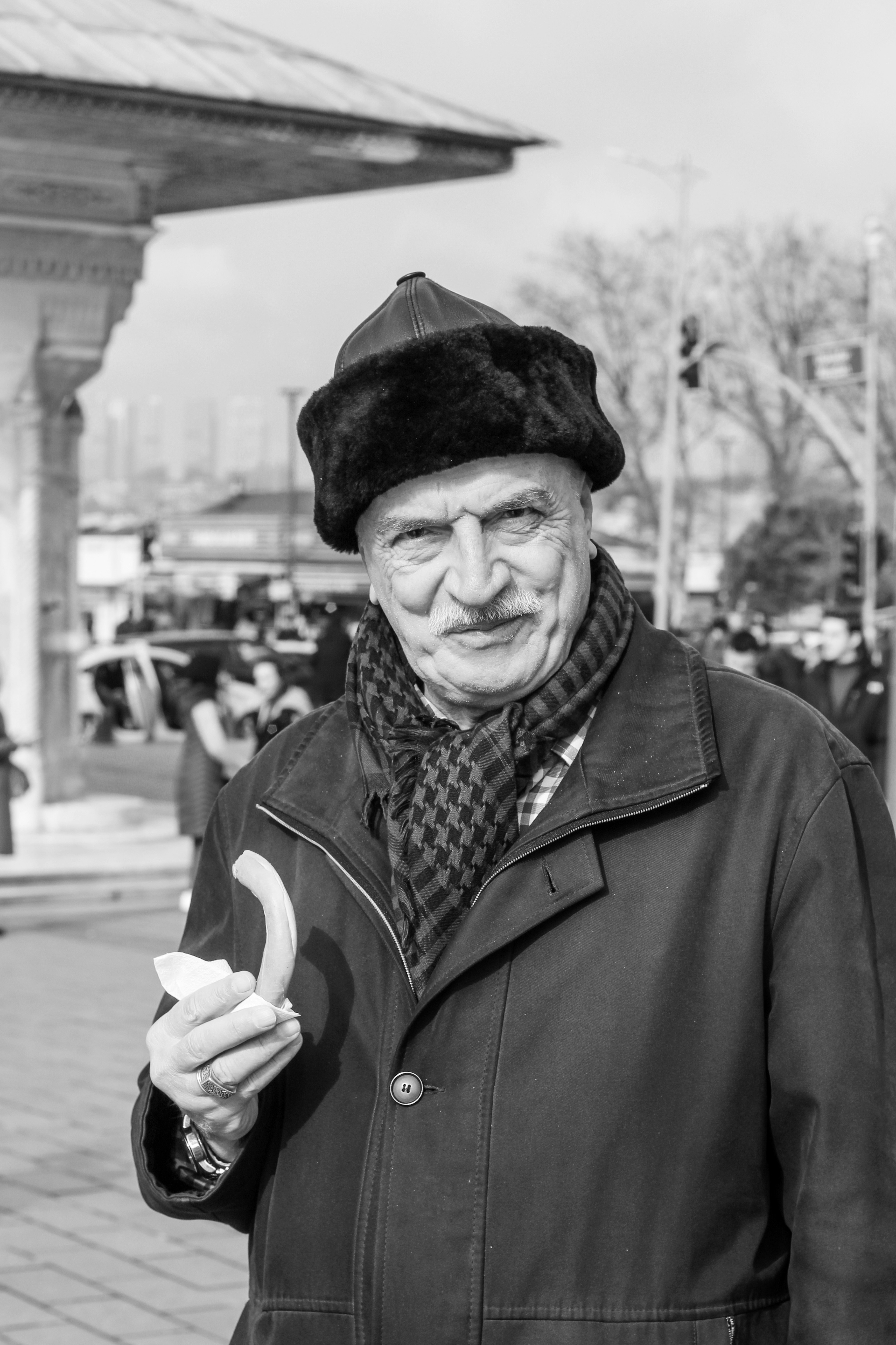 A Weathered Smile and a Snack on a Crowded Street