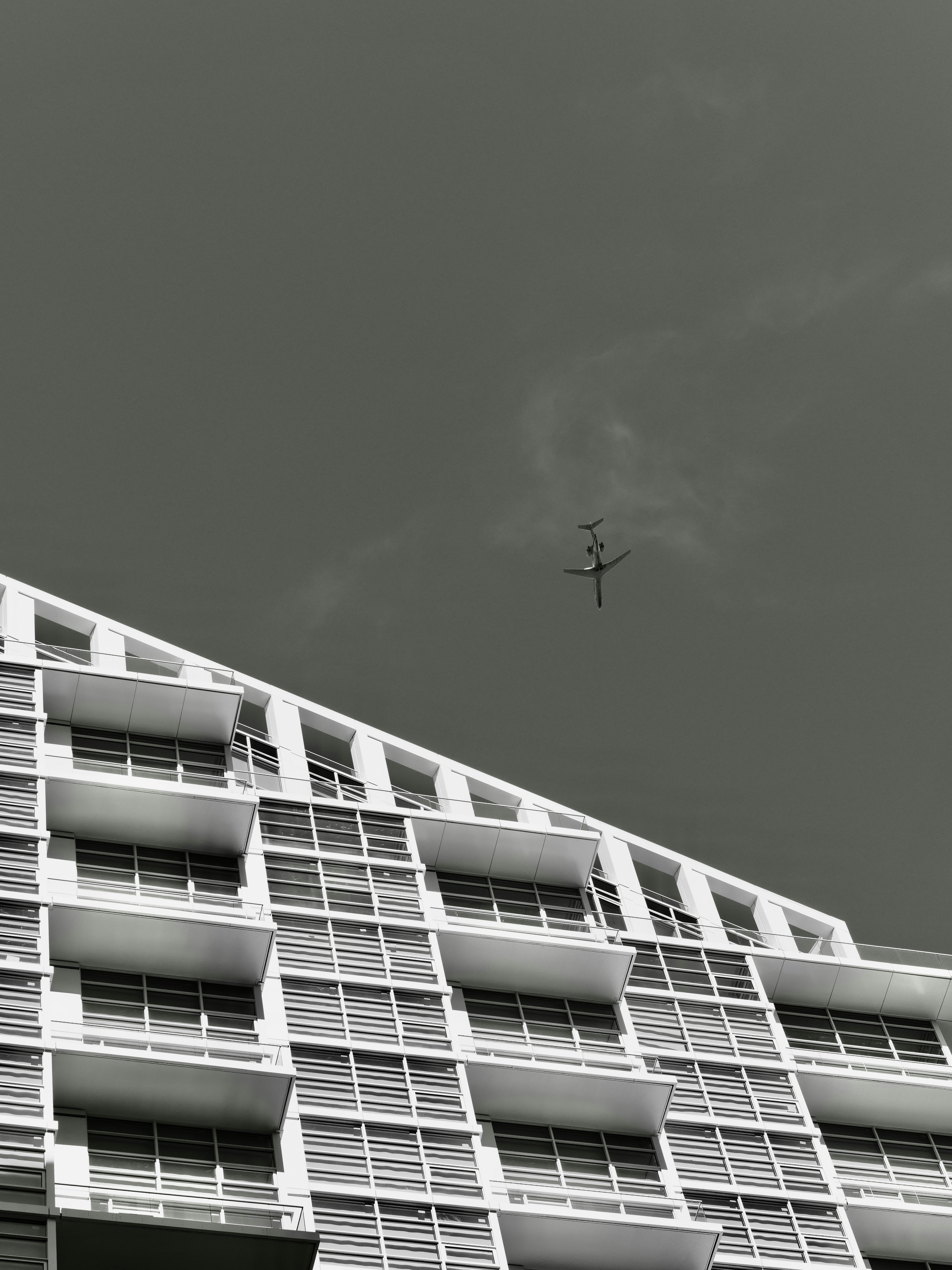 Monochrome Facade Beneath a Floating Aircraft