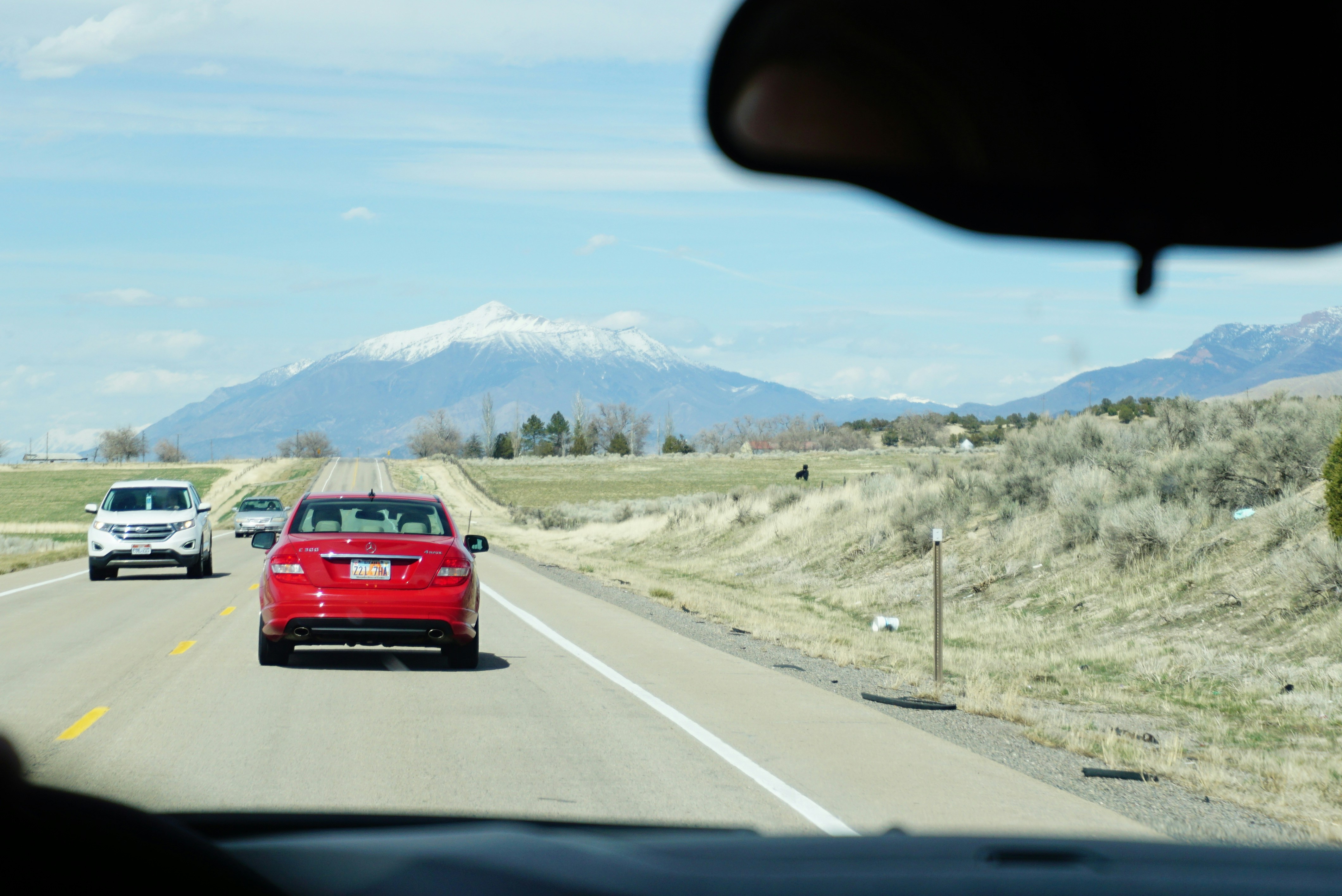 Red Hatch on a Desert Highway toward Snow-Capped Peaks