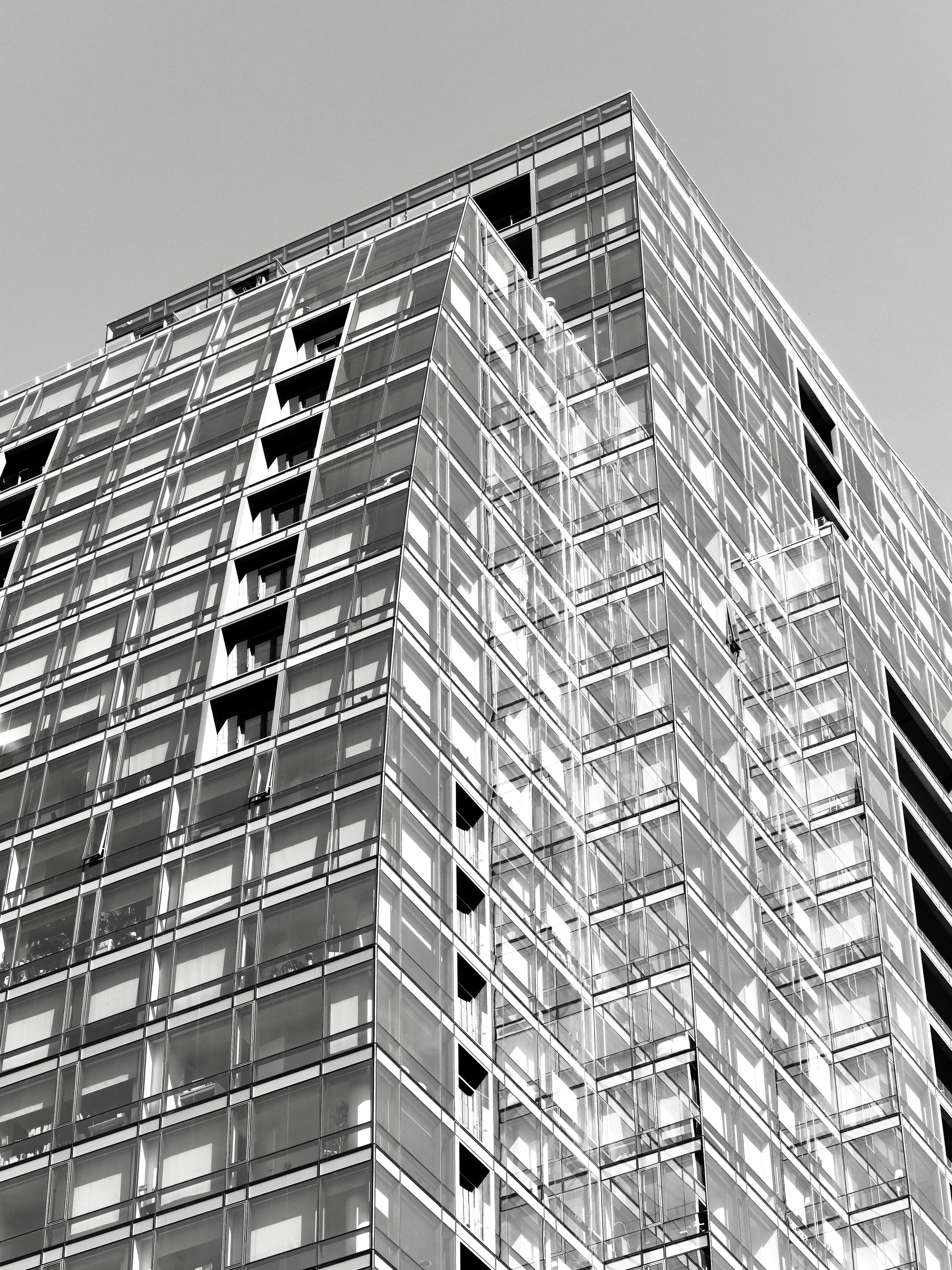 Geometric Facade: A Tilted Glass Tower in Monochrome
