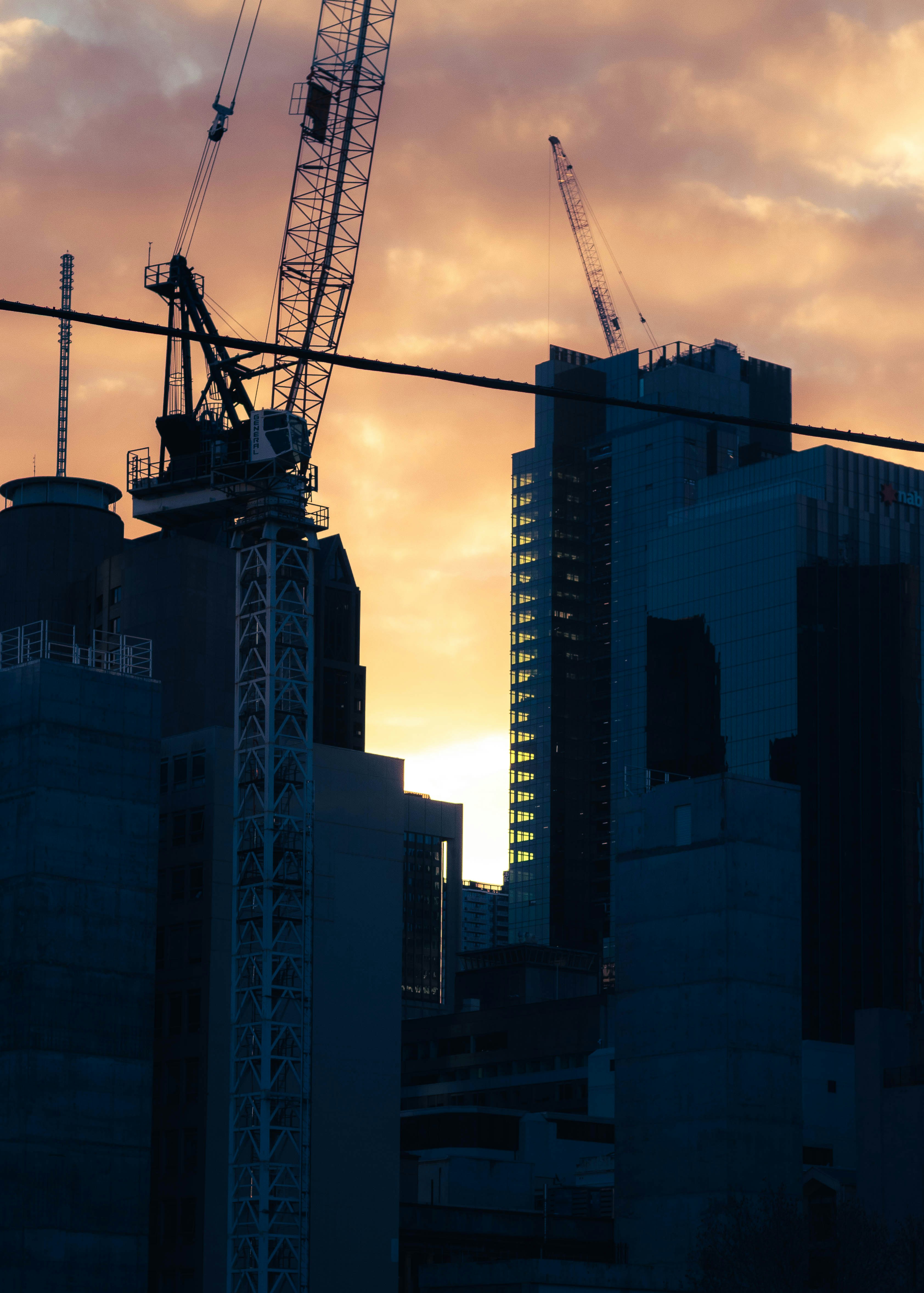 Towering Silhouette at Dusk: Cranes Against a City Sky