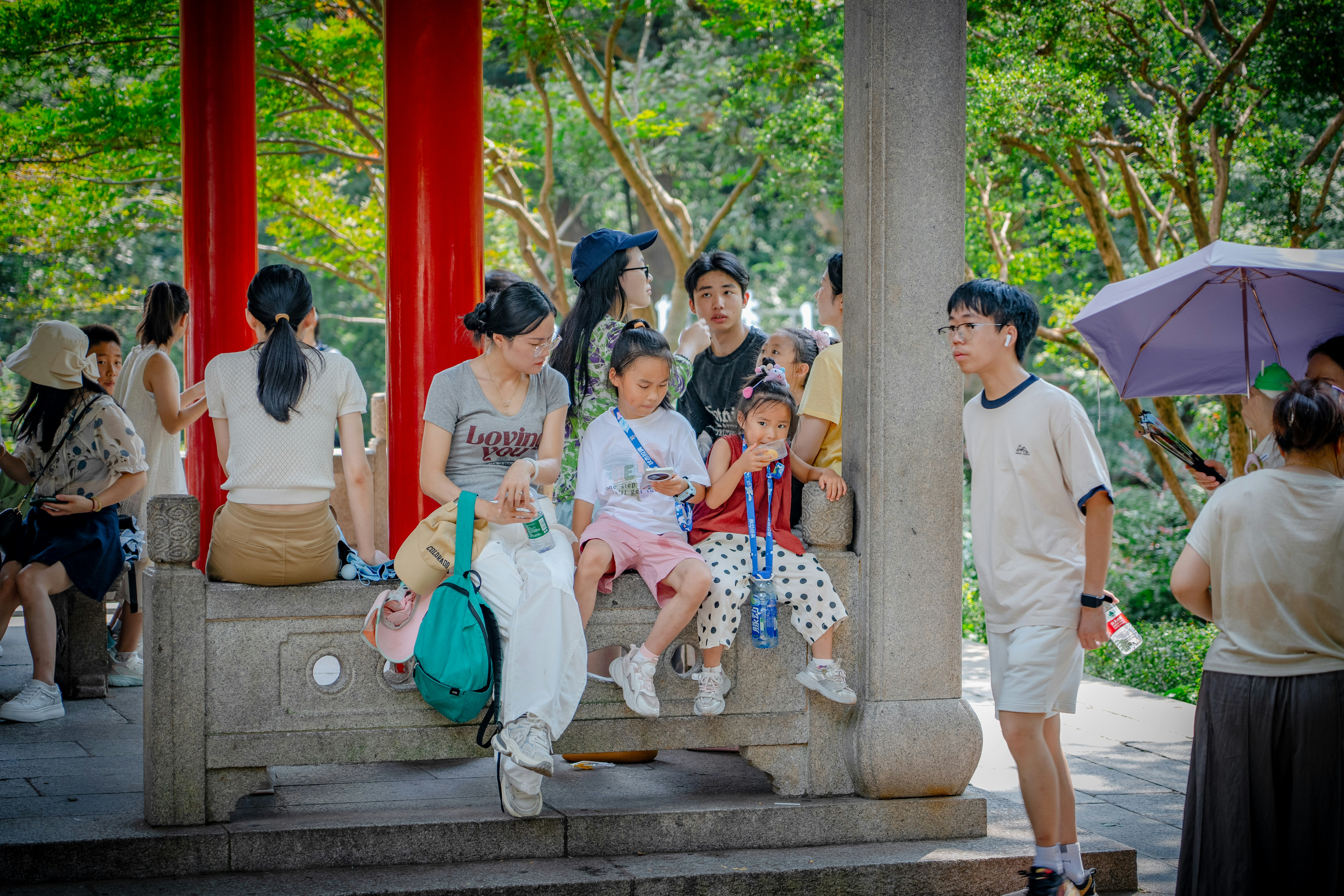Shaded Courtyard Pause: Family Gathering on a Stone Bench