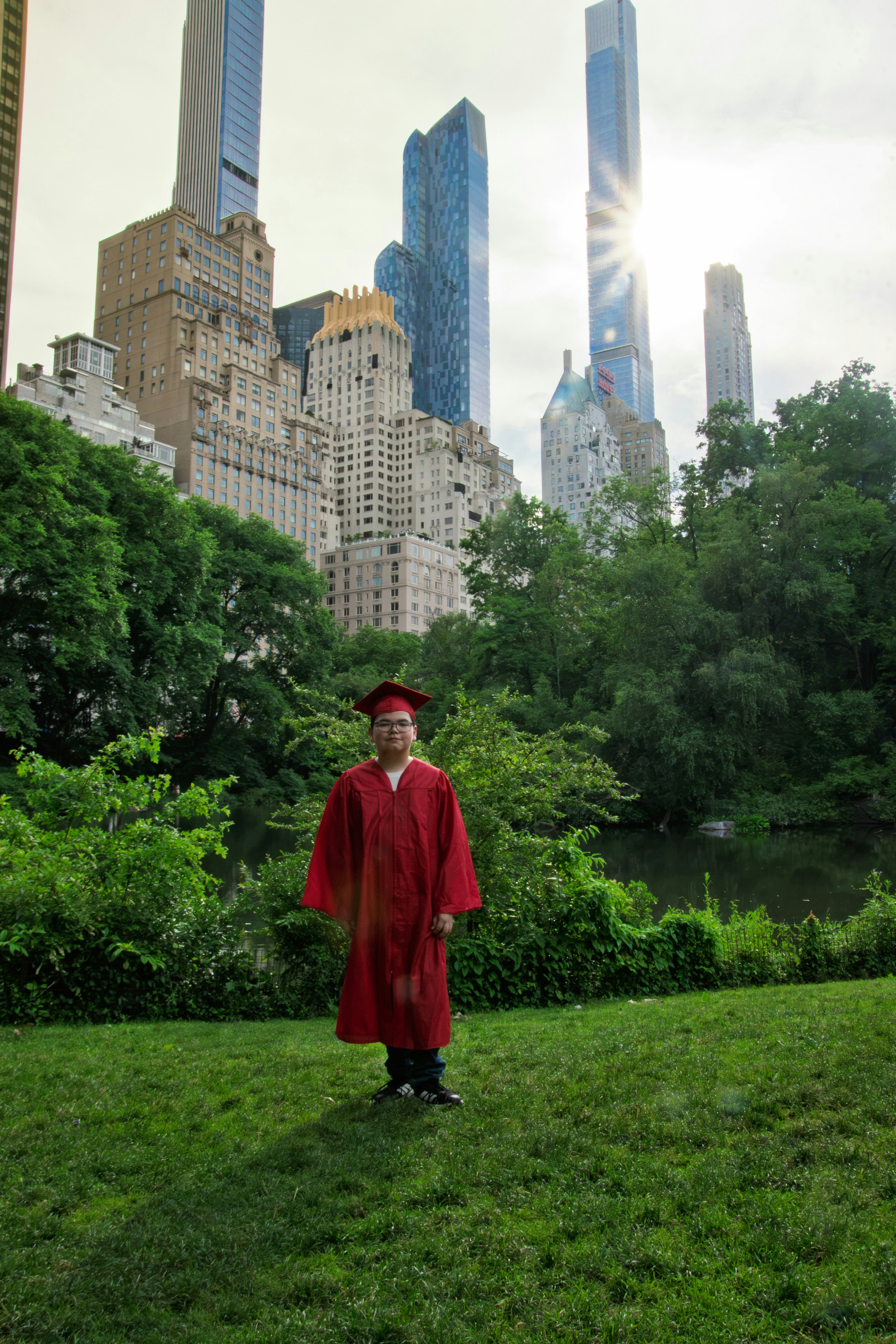 Graduate in the City Park: A Red Gown in Front of Skyline Gleam