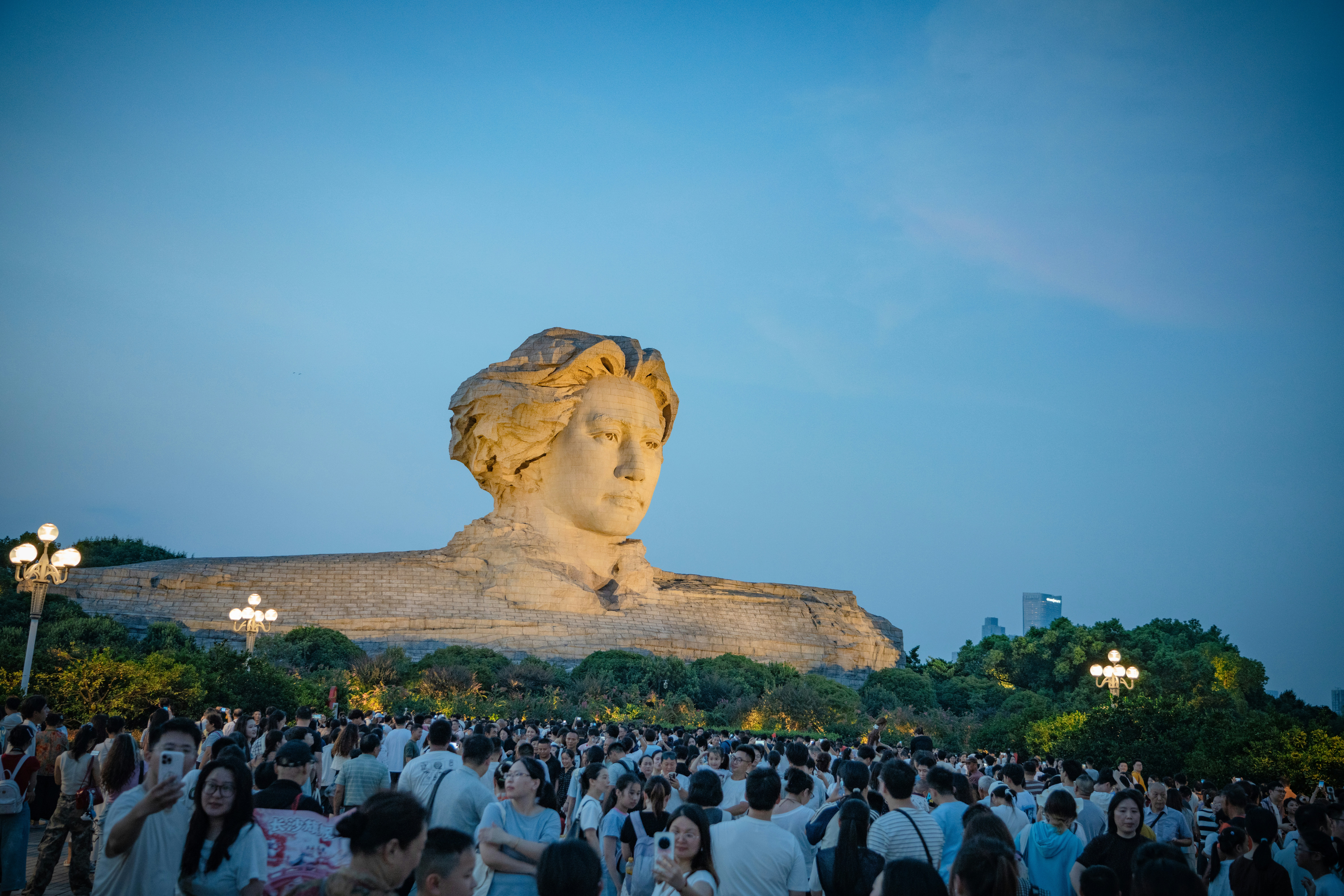 Evening at the Monument: Faces Gathered Under a Giant Rock Sculpture