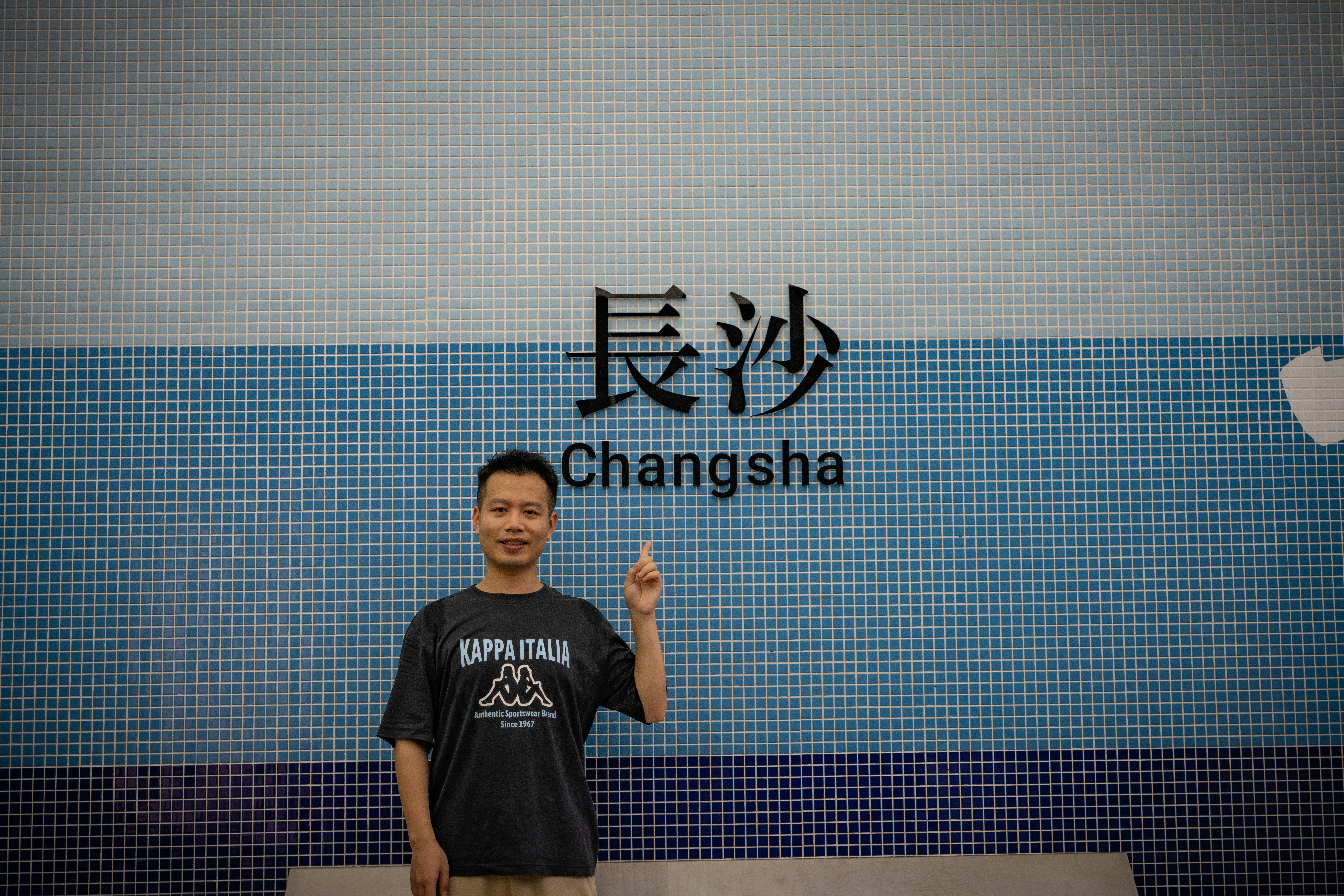 Man gesturing beside a tiled wall at Changsha station