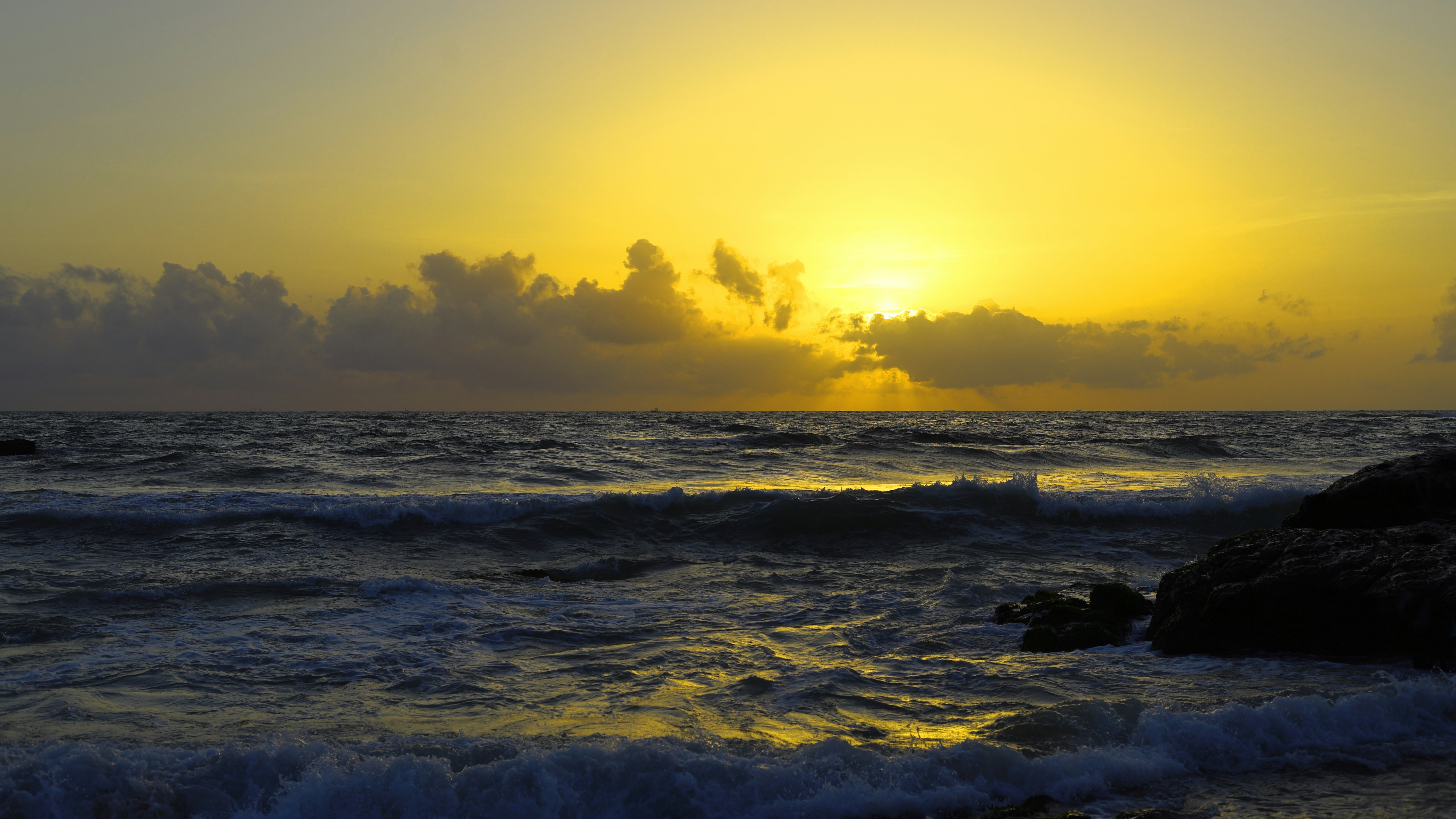 Sunlit Horizon: Golden Crest of the Sea at Dusk