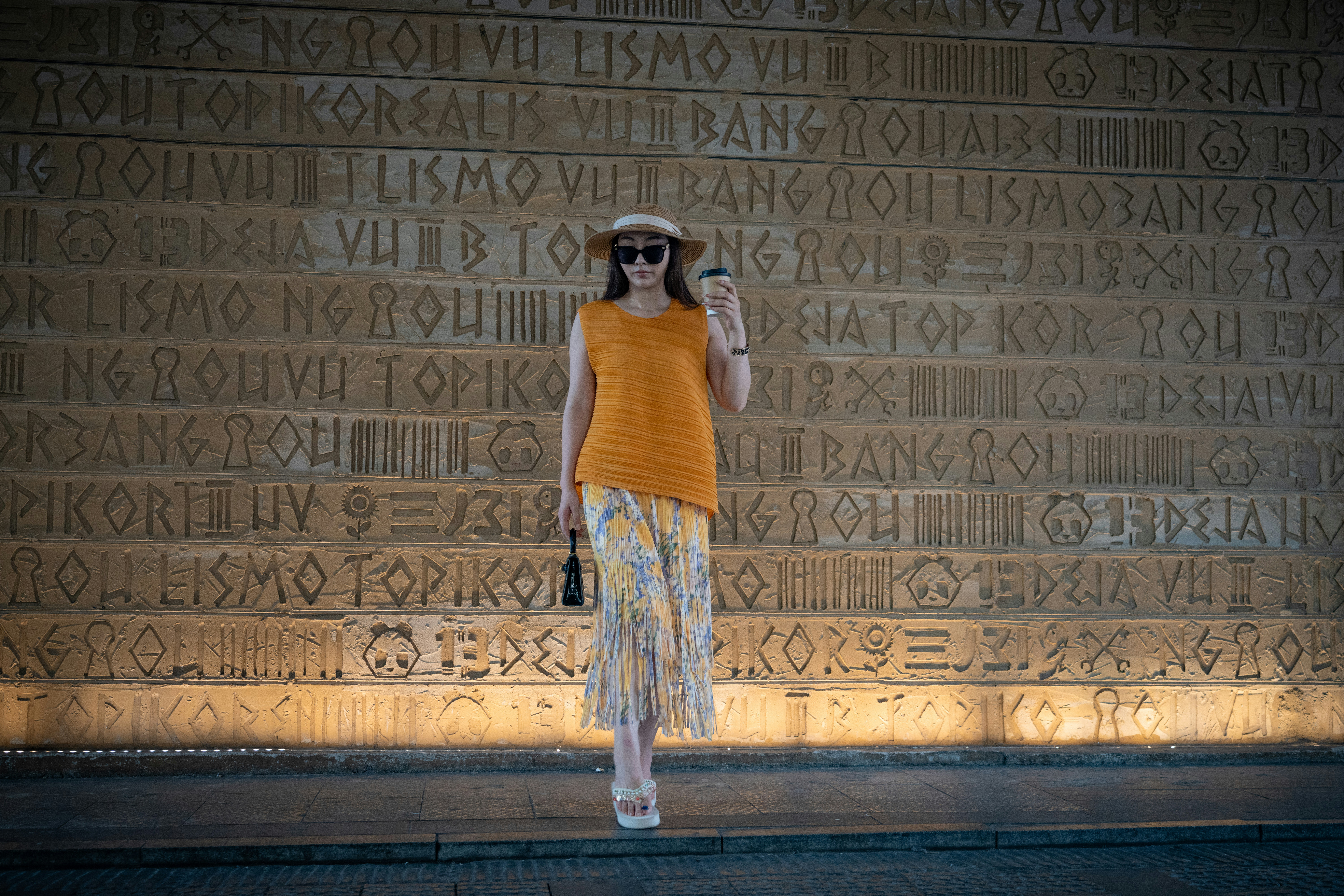 Orange Top, Sheer Skirt, and a Stony Gaze: A Solo Street Portrait in Ancient Script