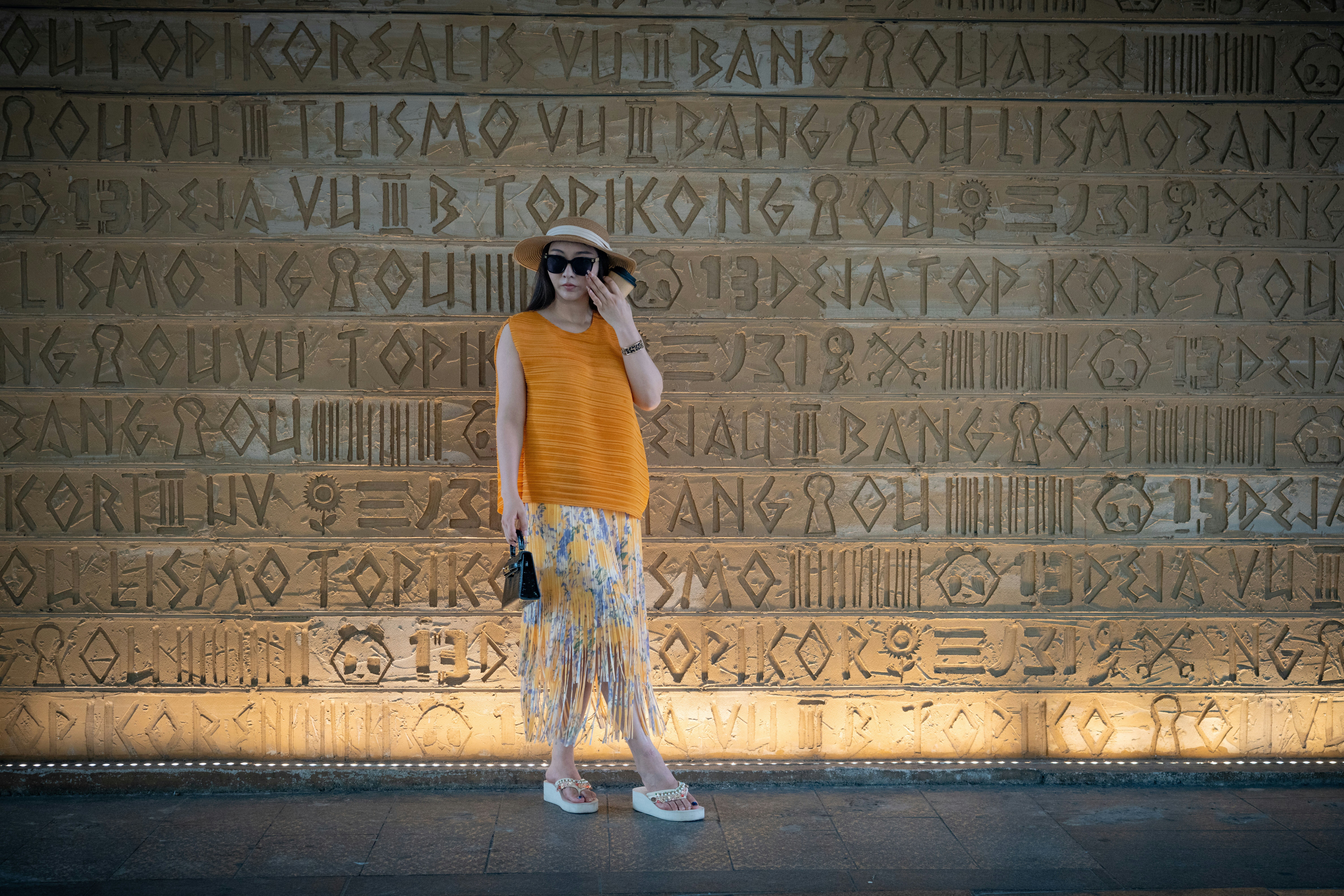 Orange Top on a Stone Stage: A Woman in Wide-Bloomed Skirt Beneath Ancient Script