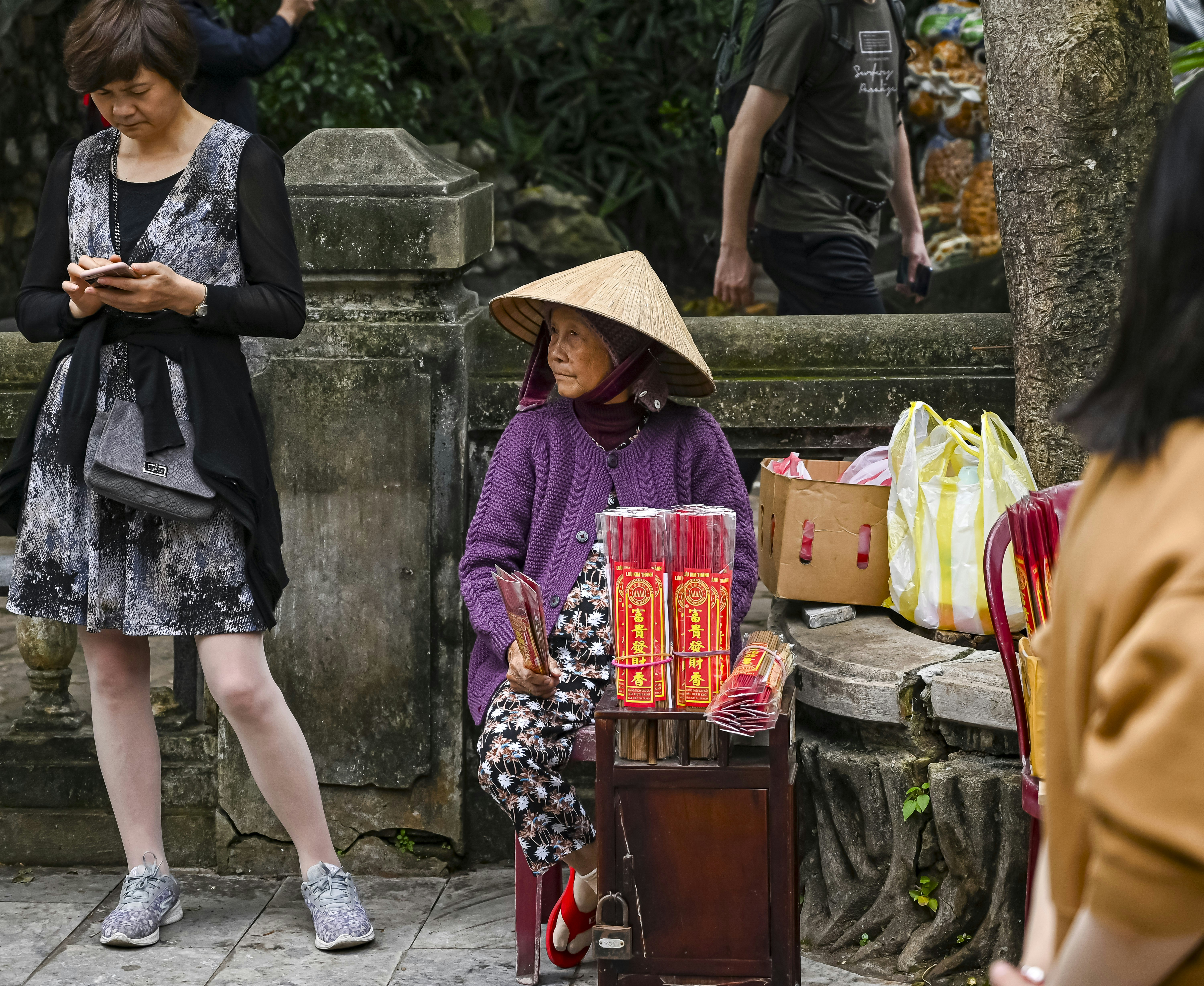 Street Vendor Under a Conical Hat: Quiet Orange Market Moment