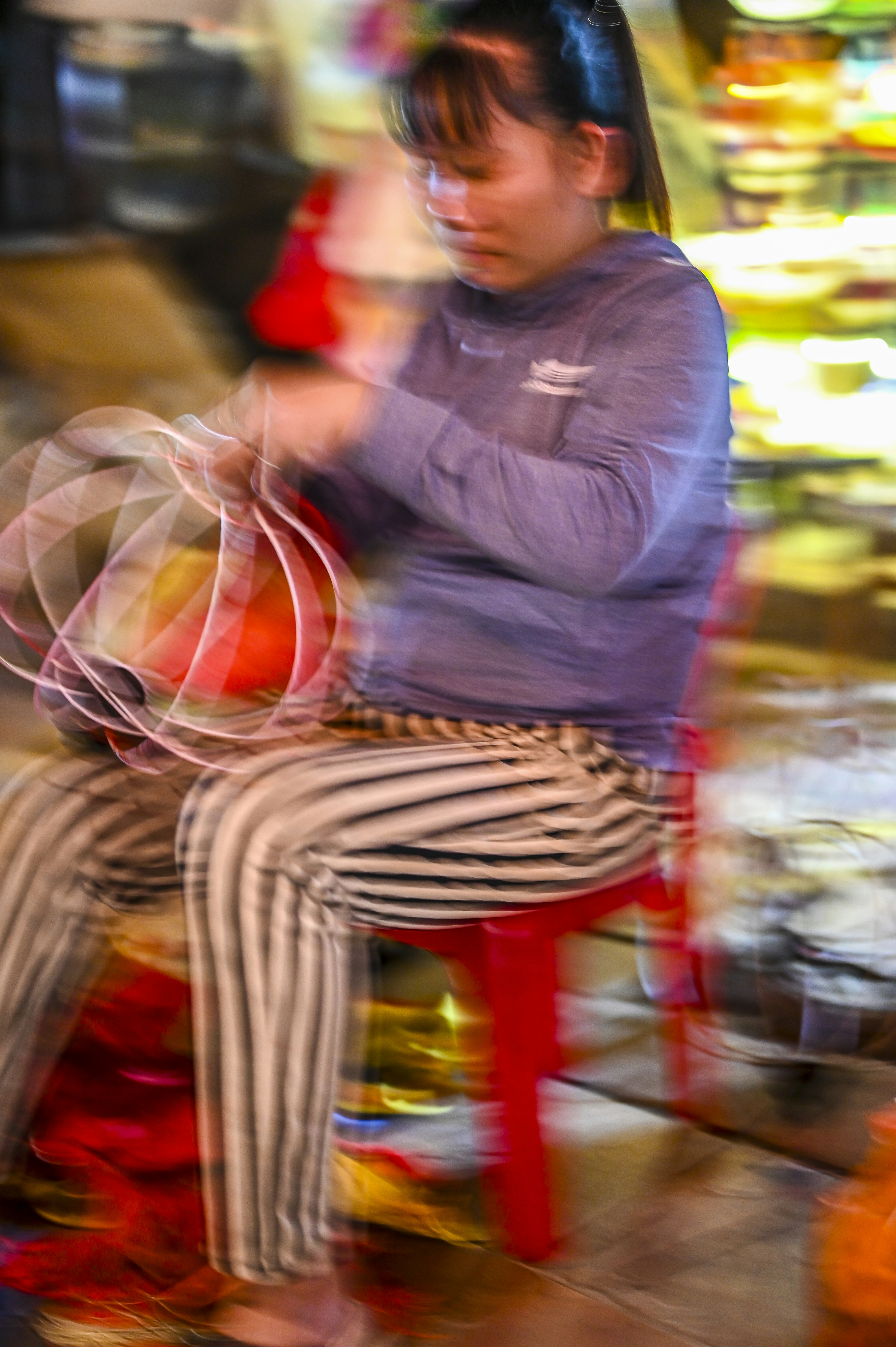 Blurred Motion at a Busy Street Stall: A Woman in Striped Pants