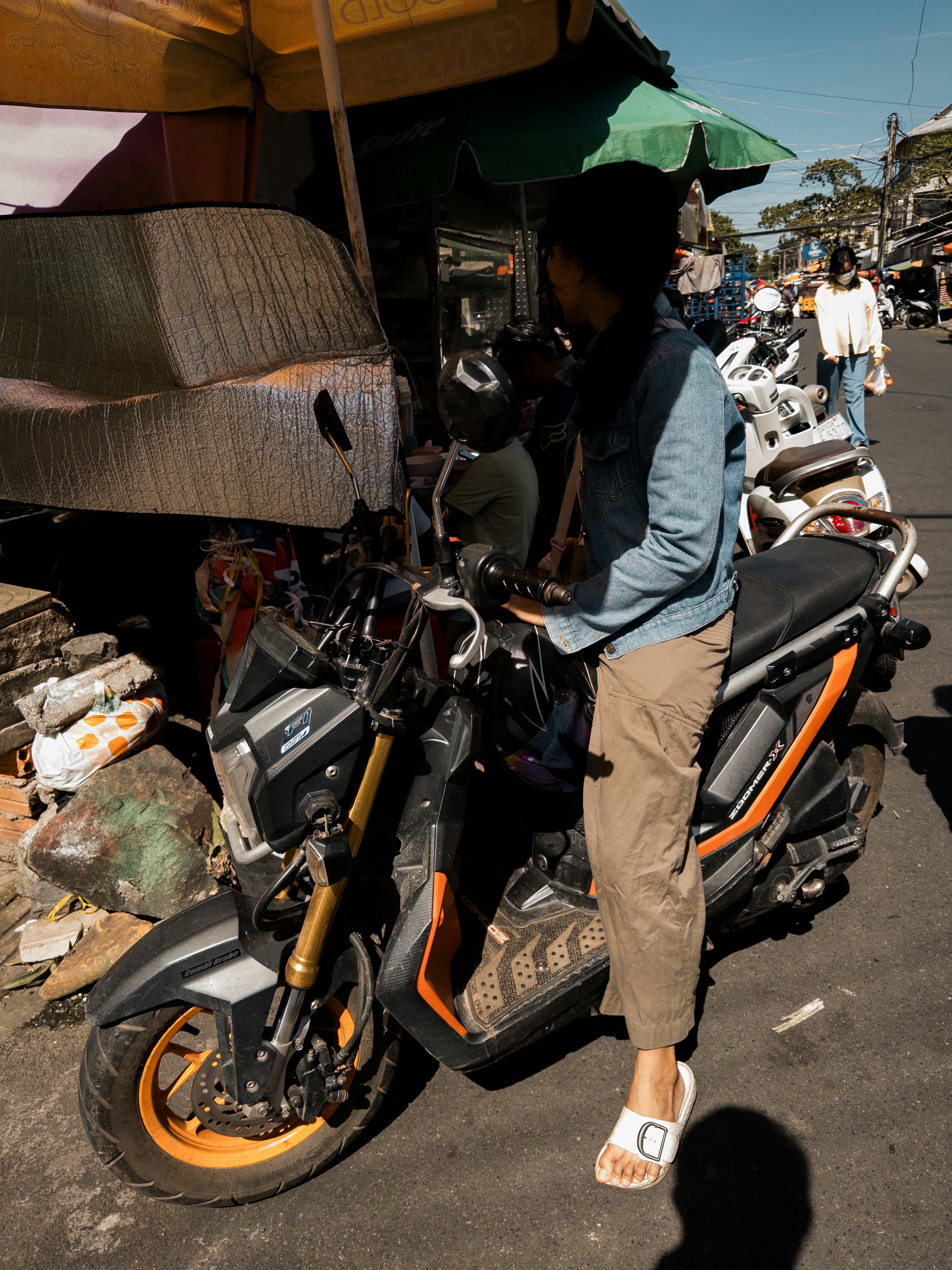 Street Rider on a Bright Orange-Accented Motorcycle Under A Market Canopy
