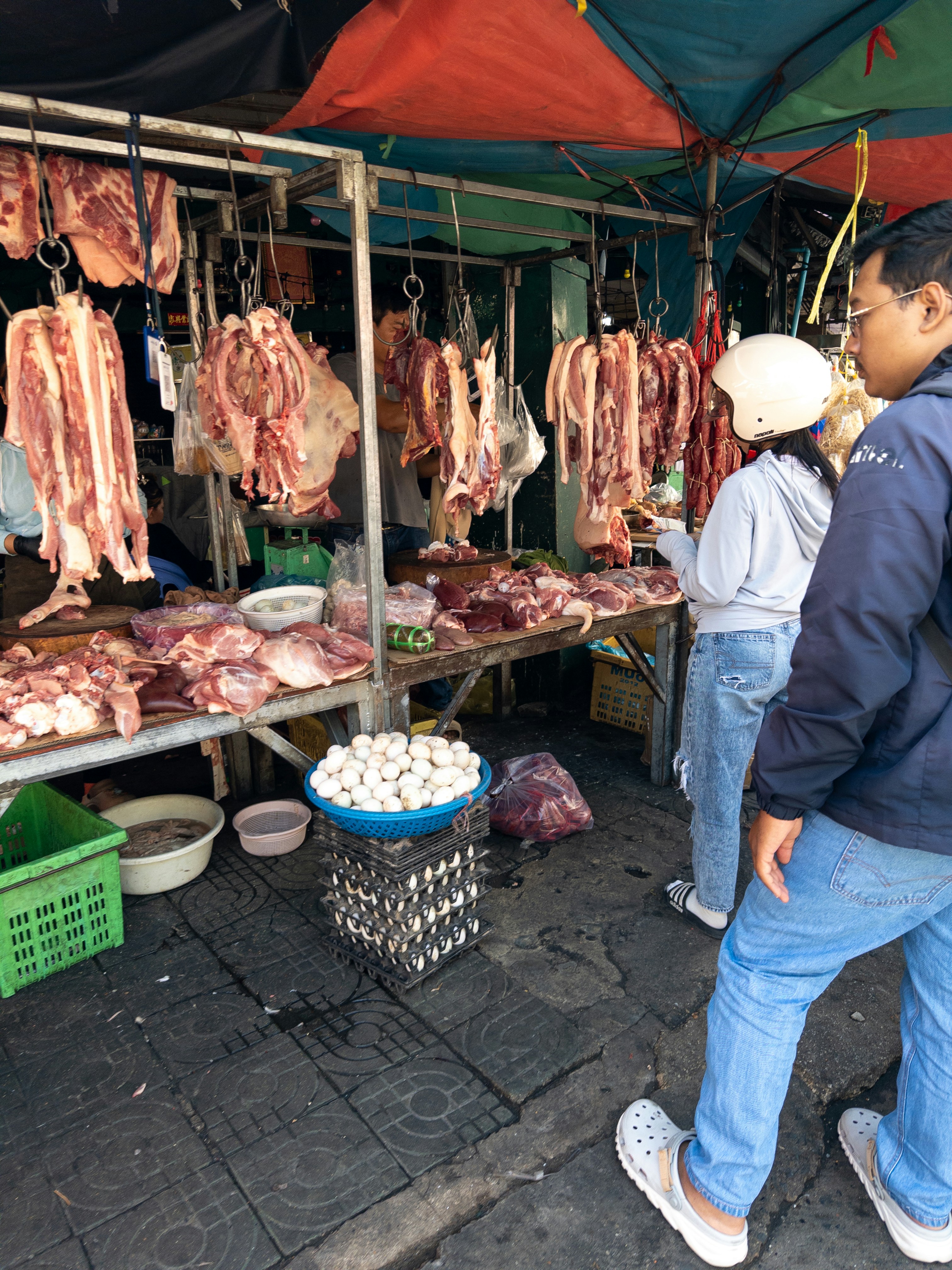 Market Butchery Stall: Hanging slabs and a crowd around fresh eggs