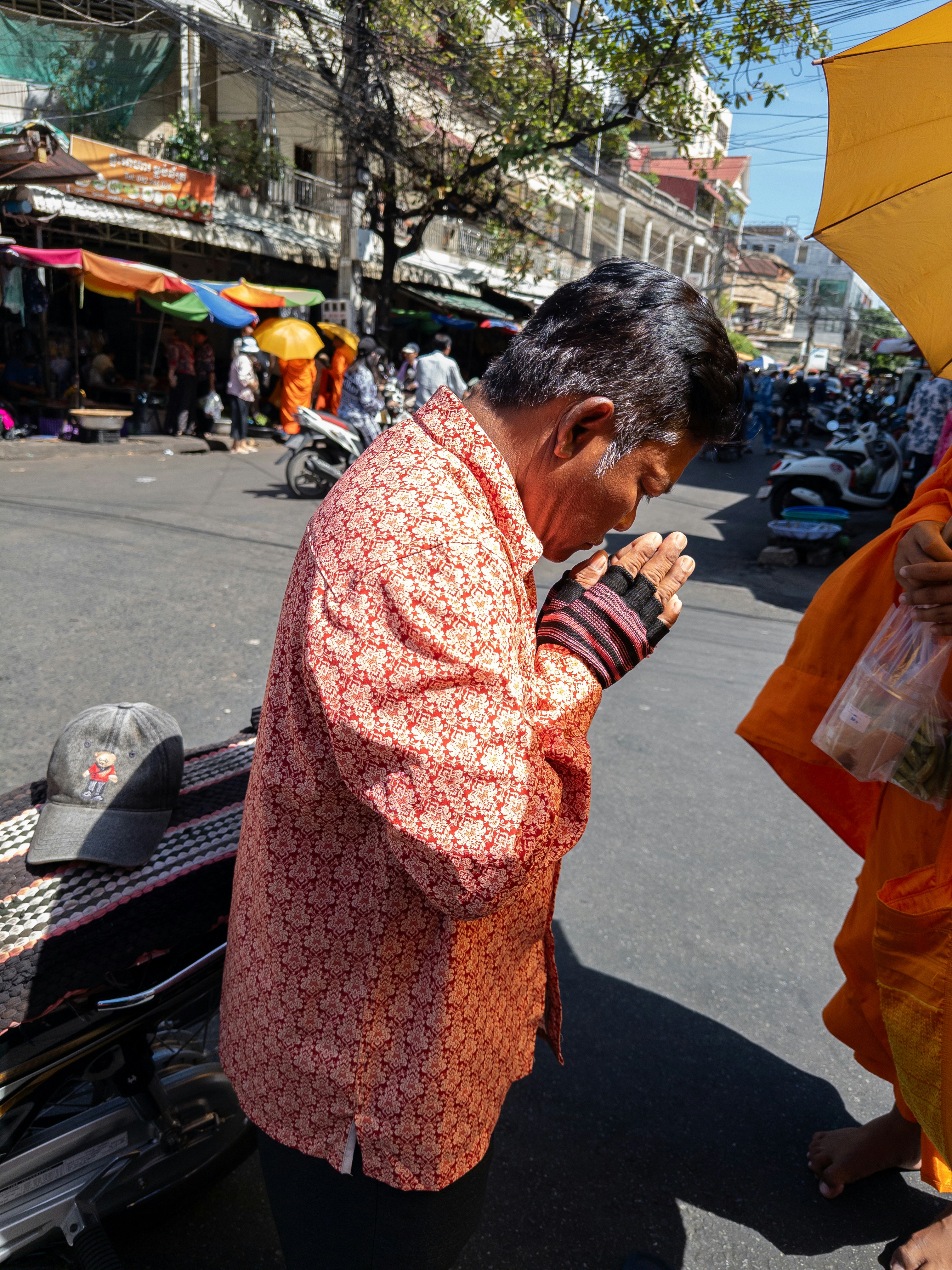 Hennaed hands in prayer on a sunlit street
