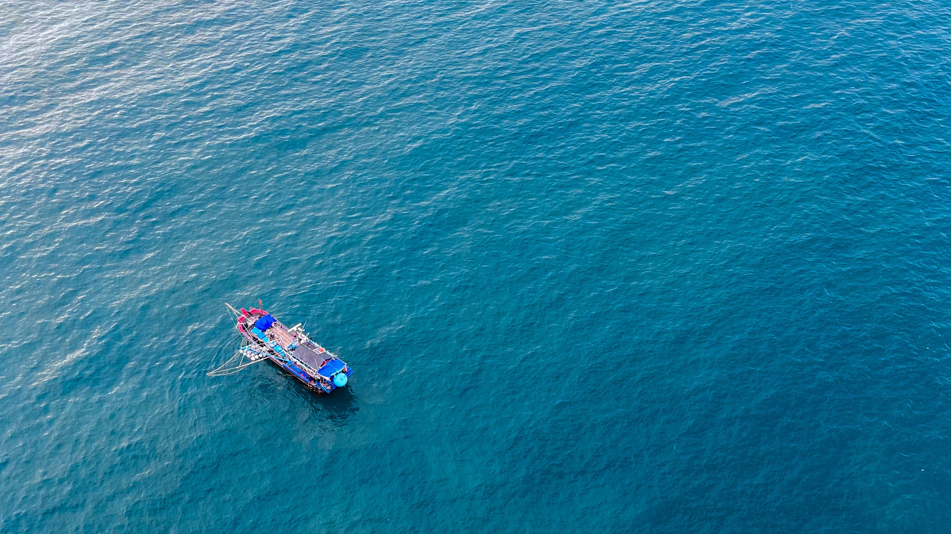 Blue Boat Adrift on Expansive Ocean Surface