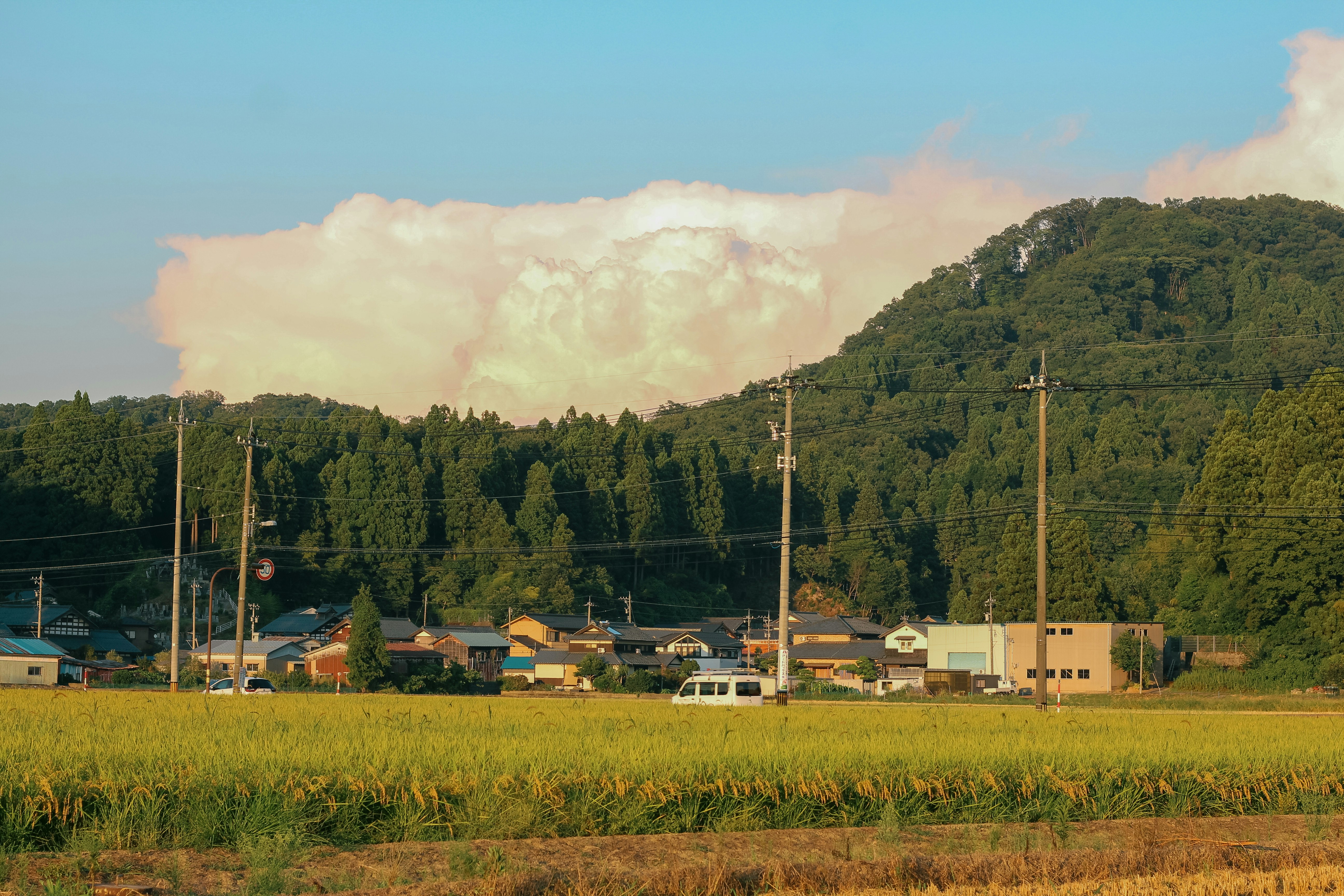 Rural village tucked at the foot of a hill under a soft sunset
