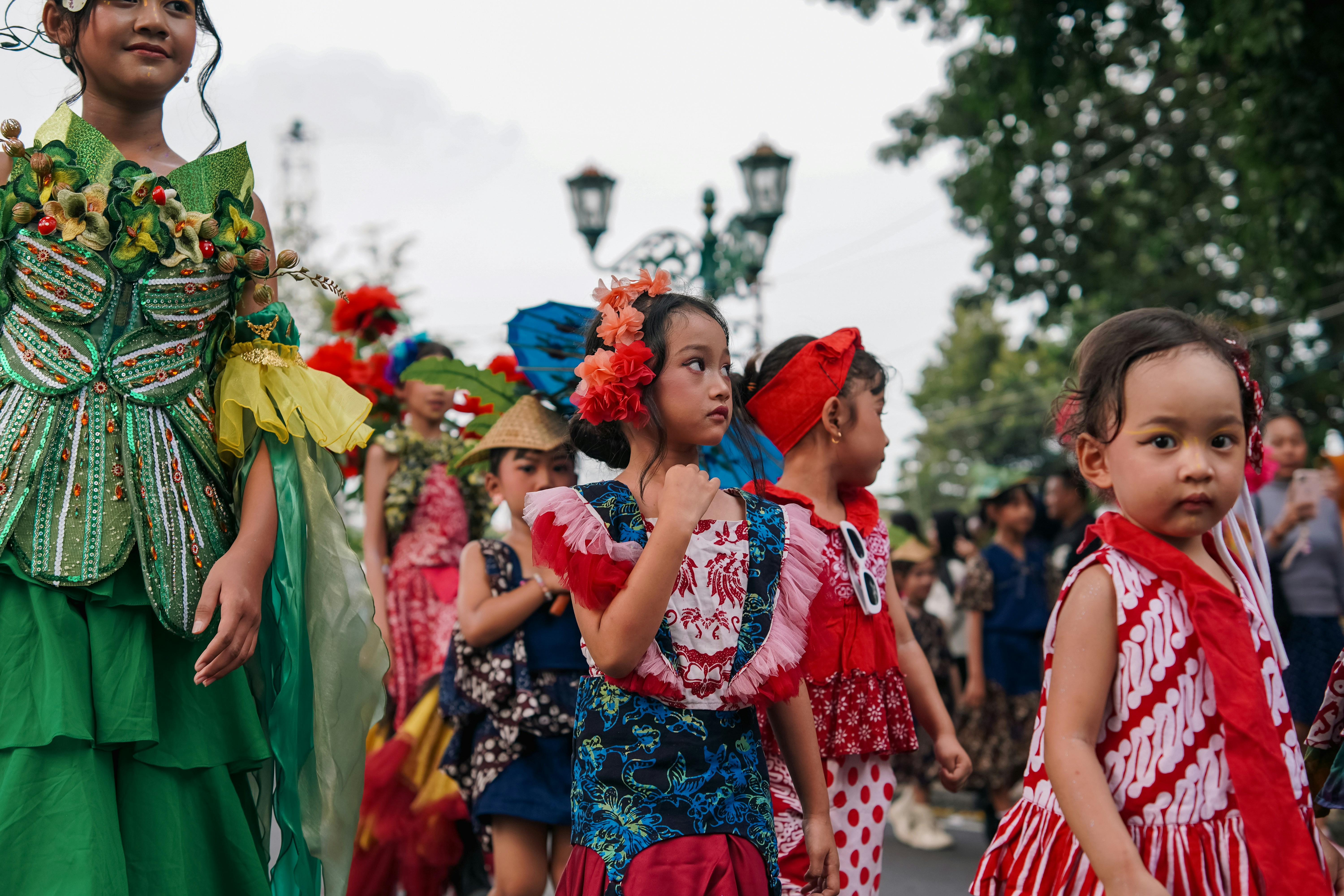 Colorful parade of children in festive costumes marching under a Parisian-like street scene