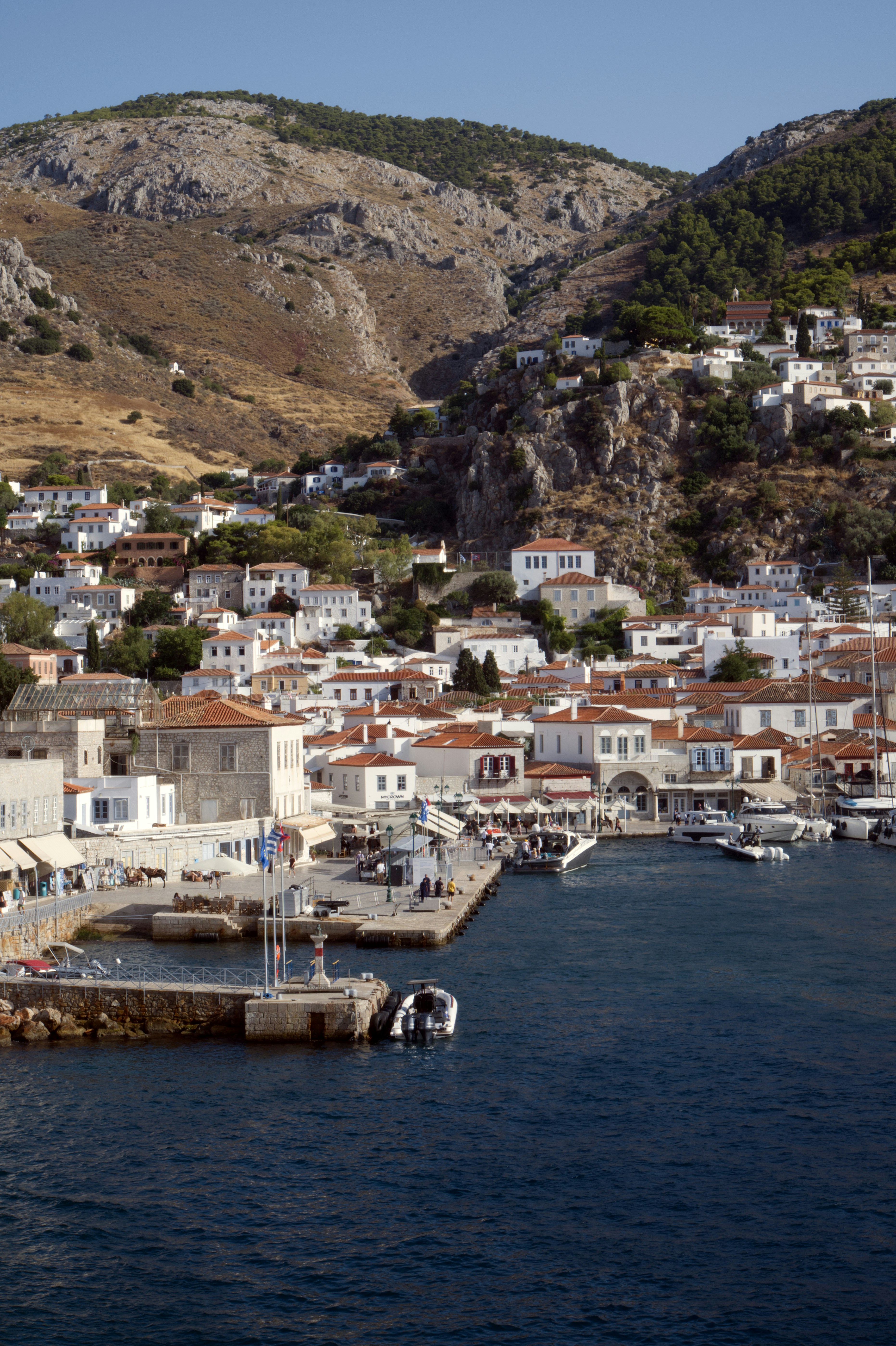 Harbor village cliffside: white-washed houses cling to rocky slopes above a sunlit harbor