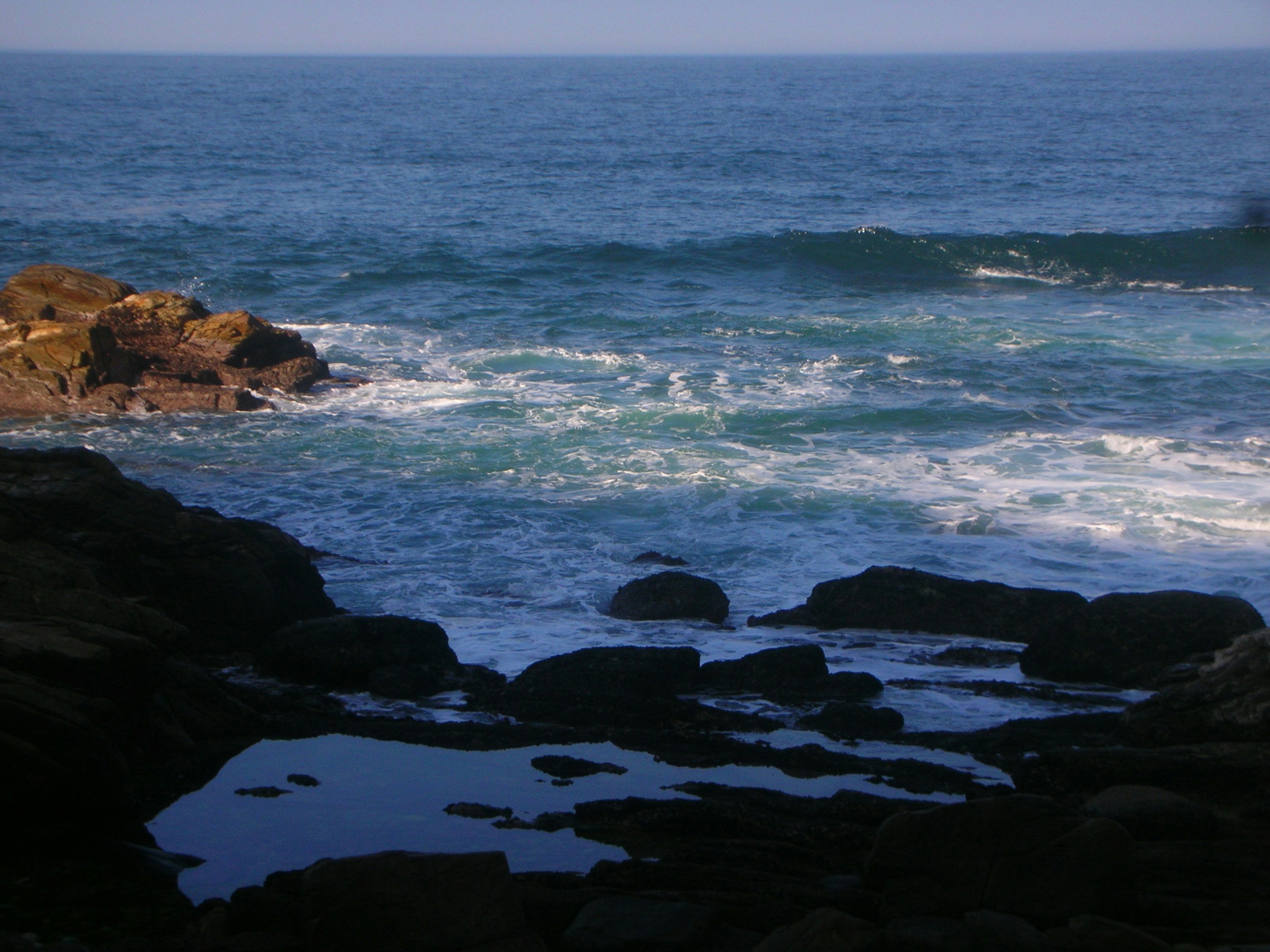 Moonlit Break: Rocks and Surf Framed by a Distant Horizon