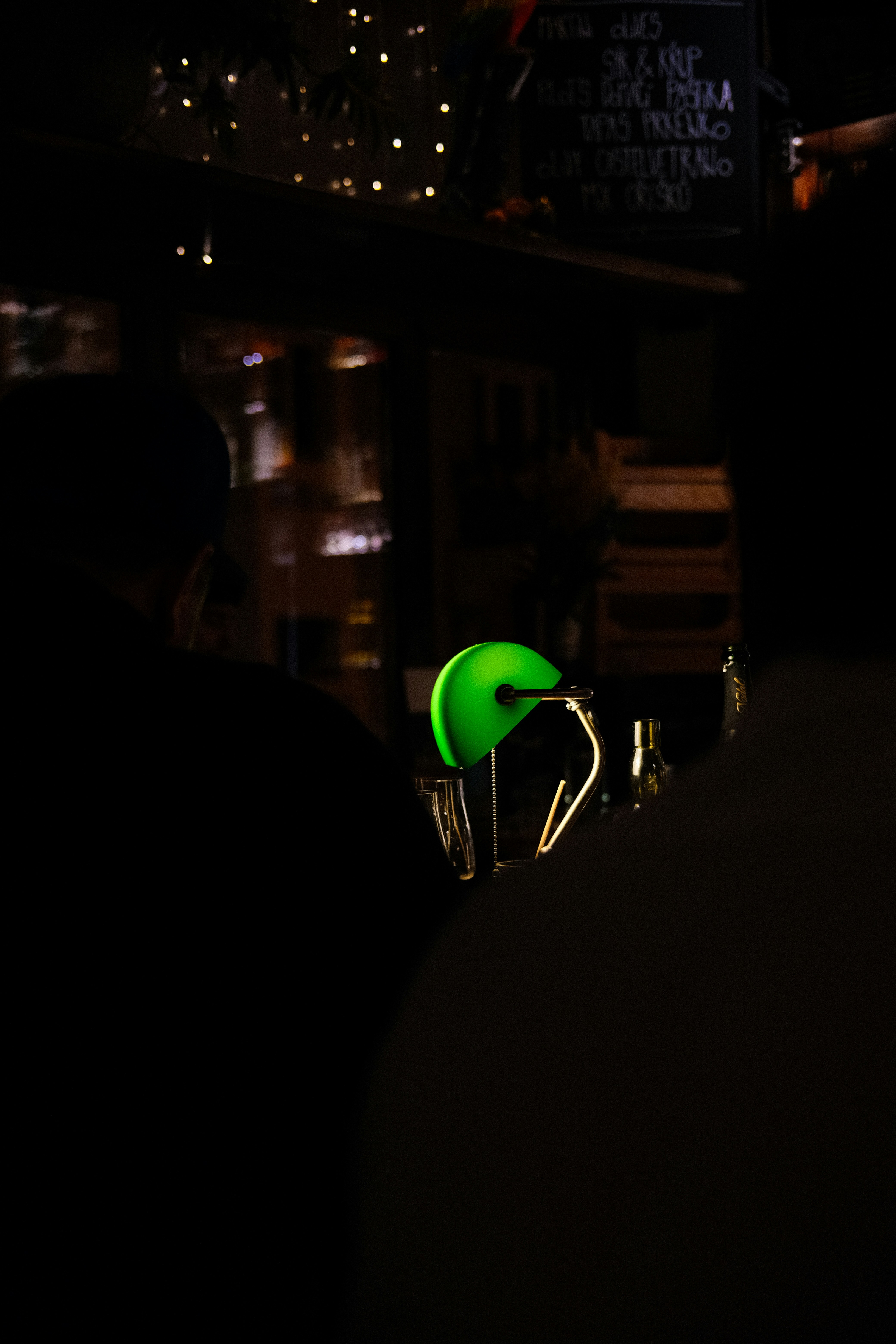 Emerald Lamp at the Bar: A Quiet Glow Amid Darkened Rooms