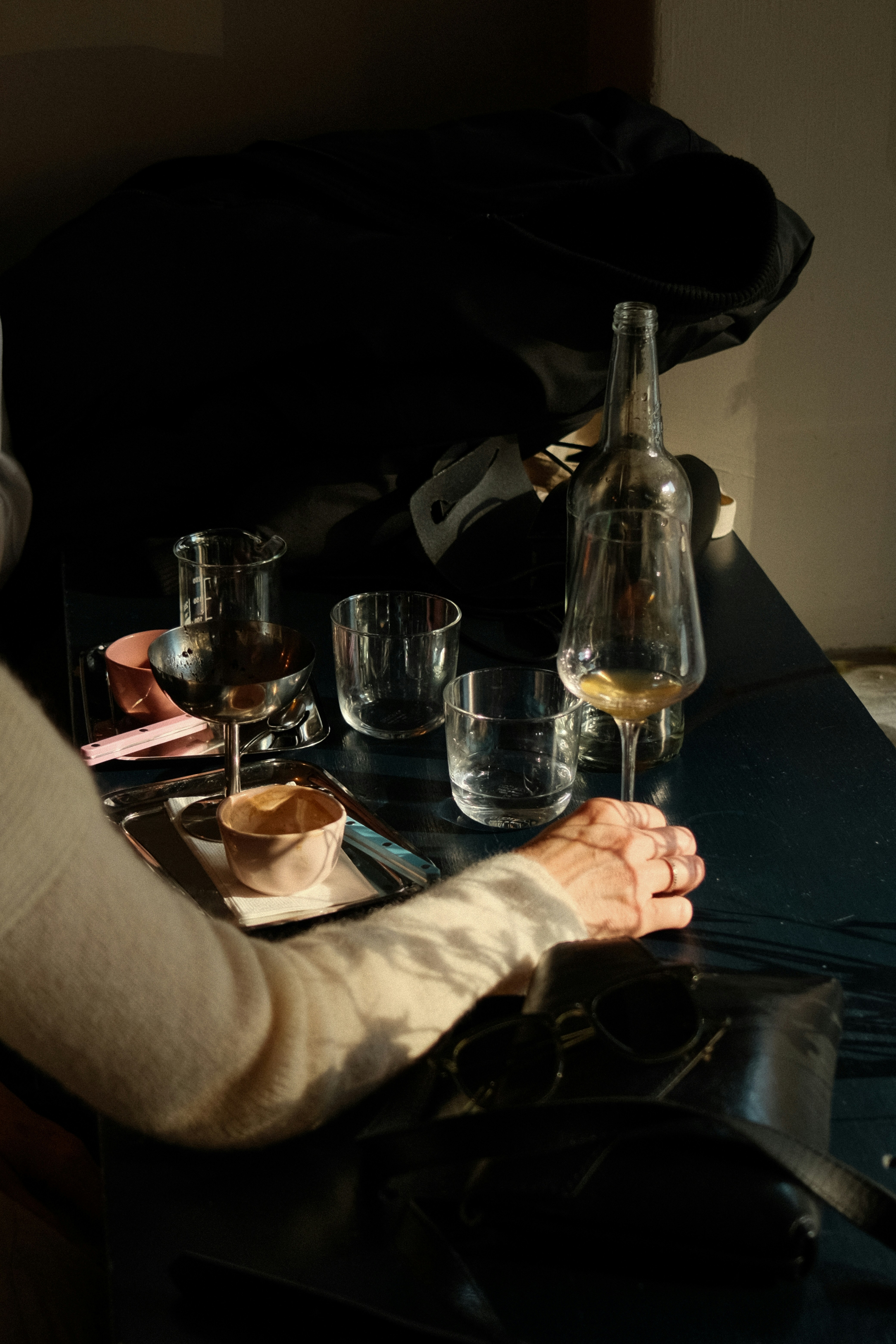 Hand and Glassware Across a Dim Table