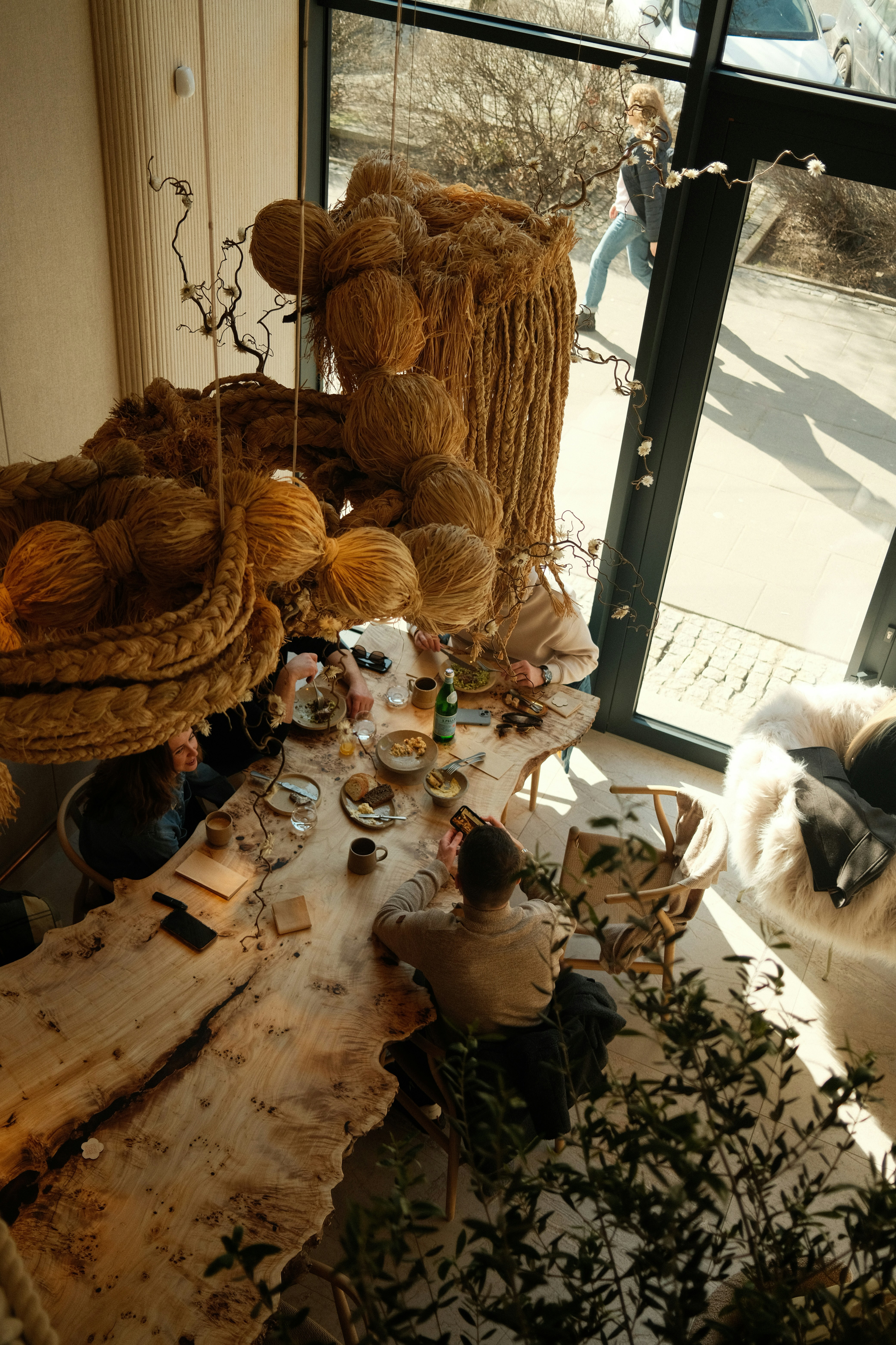 Woven centerpiece and sunlit gathering in a glass-walled cafe