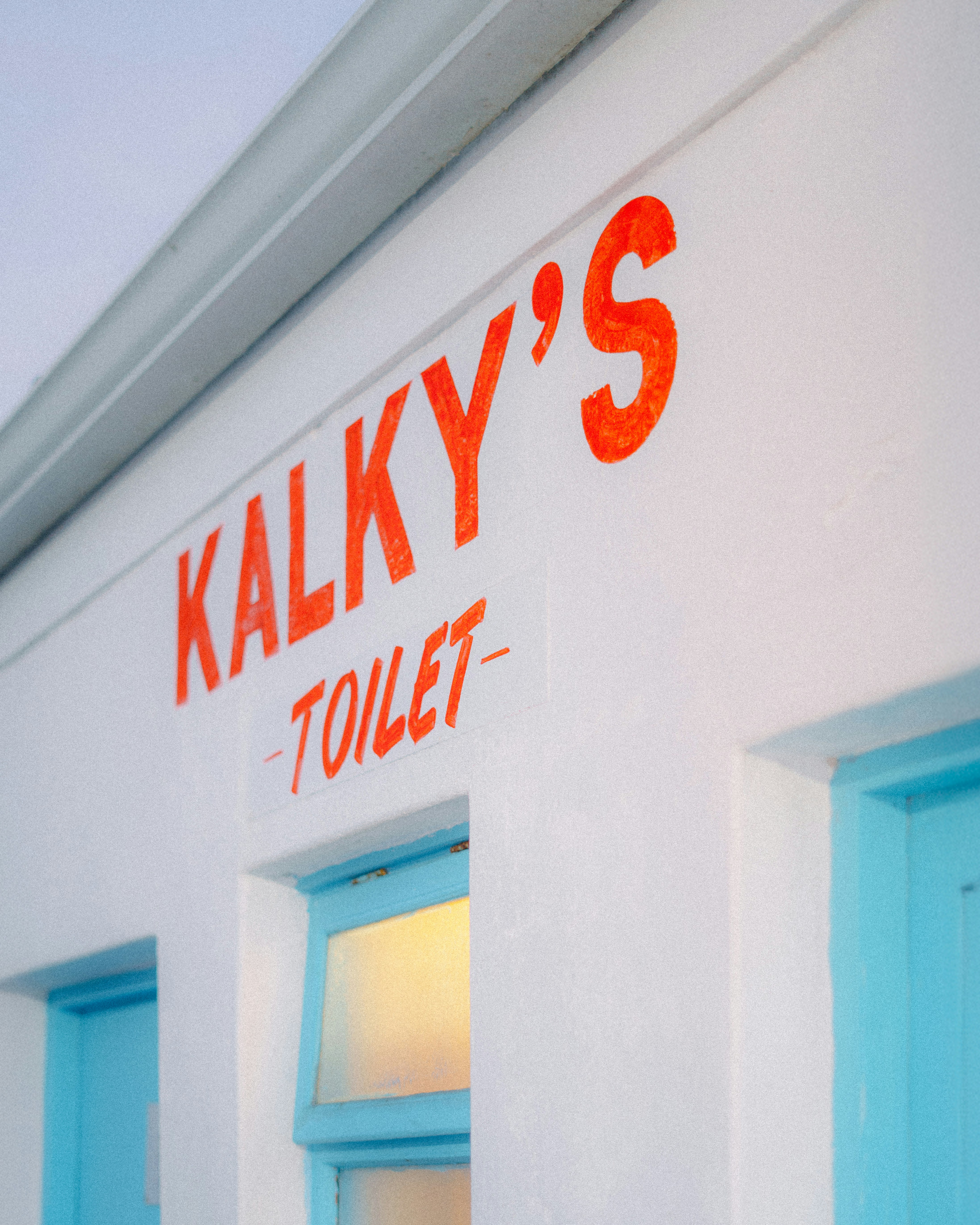 Kalky’s Toilet Signways: Bright Blue Frames on White Facade