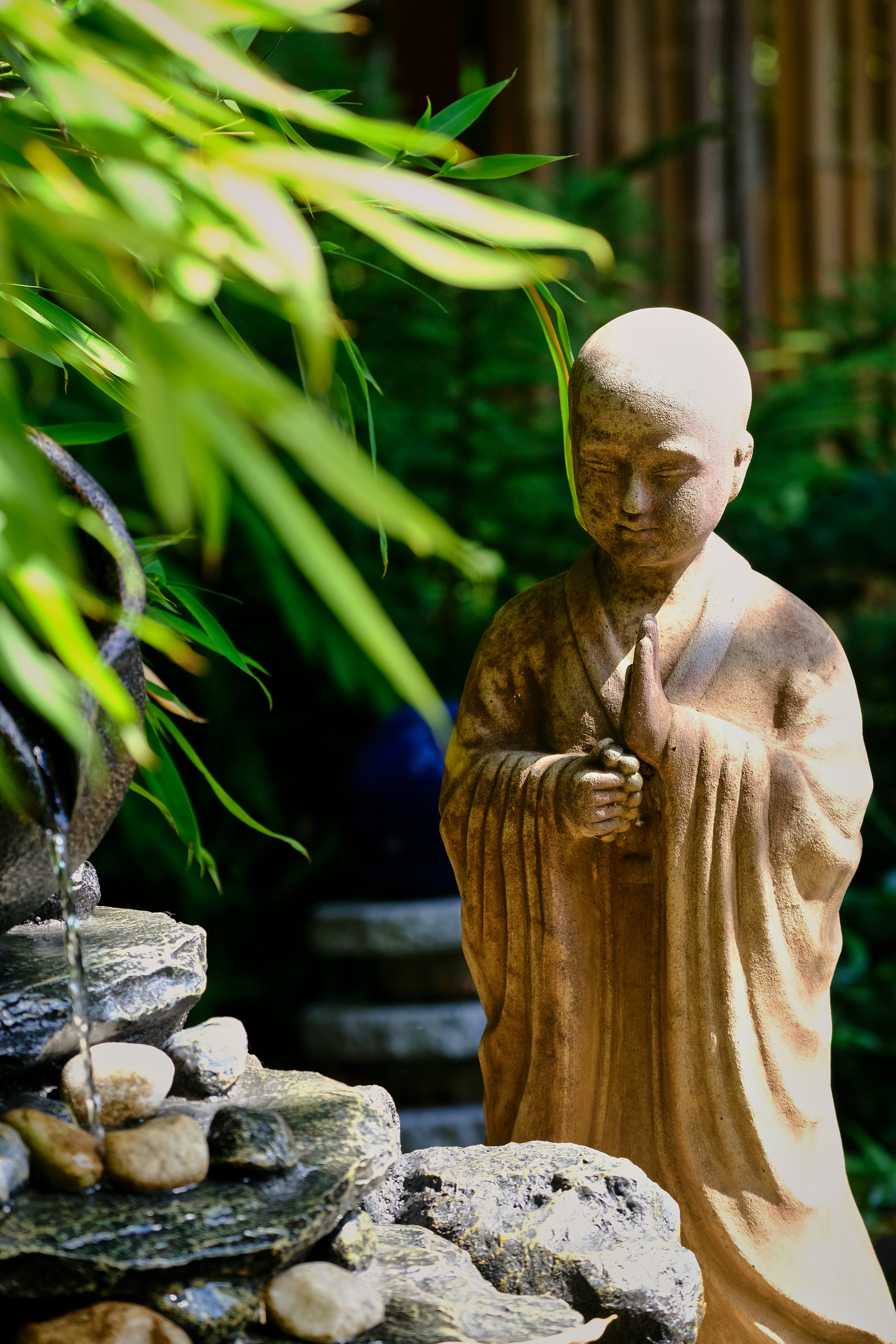 Zen Stone: Small Buddha Nestled Among Greens and Stone Rounds