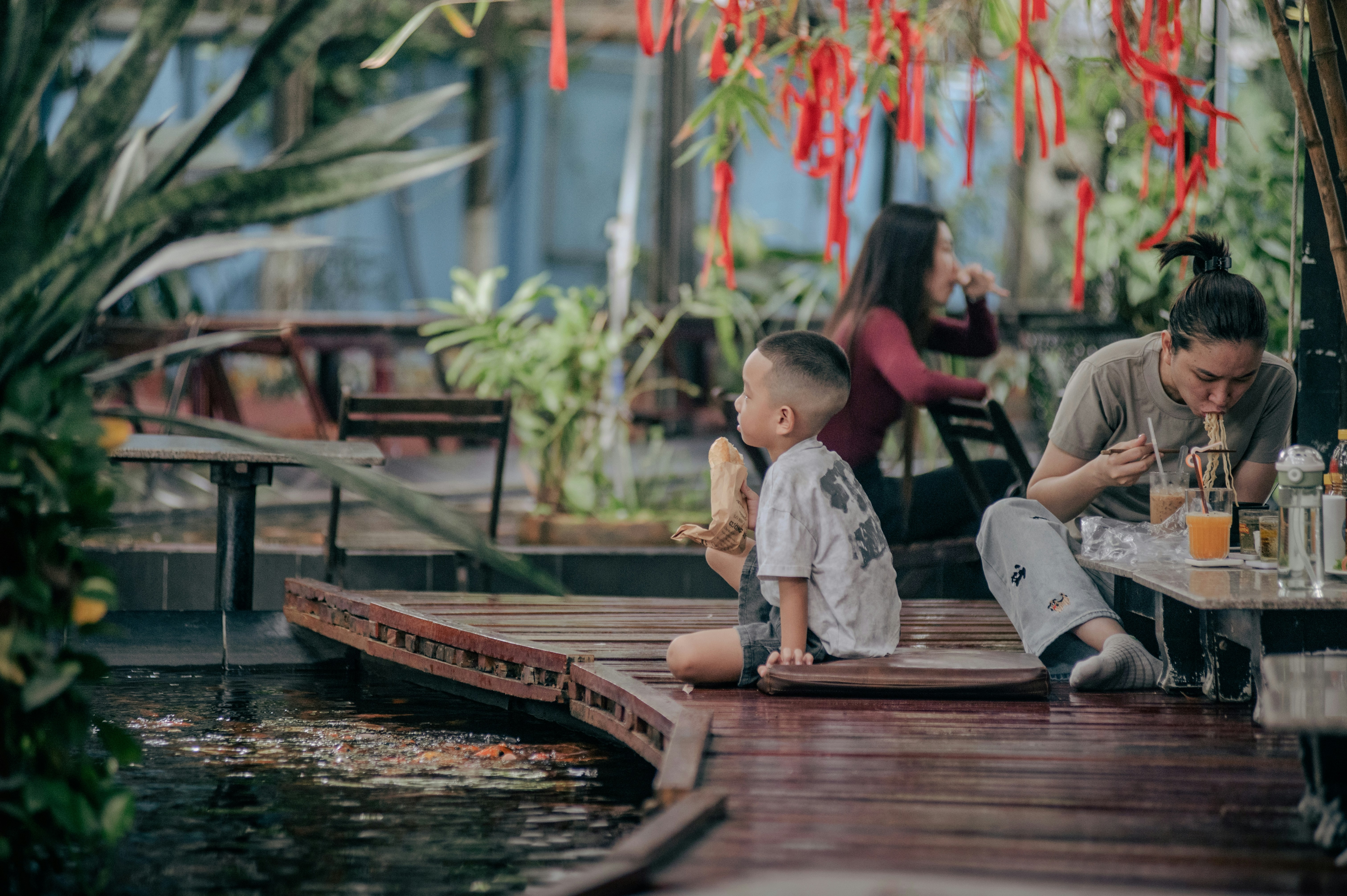 Quiet moments by the wooden pond: children and diners on a riverside deck