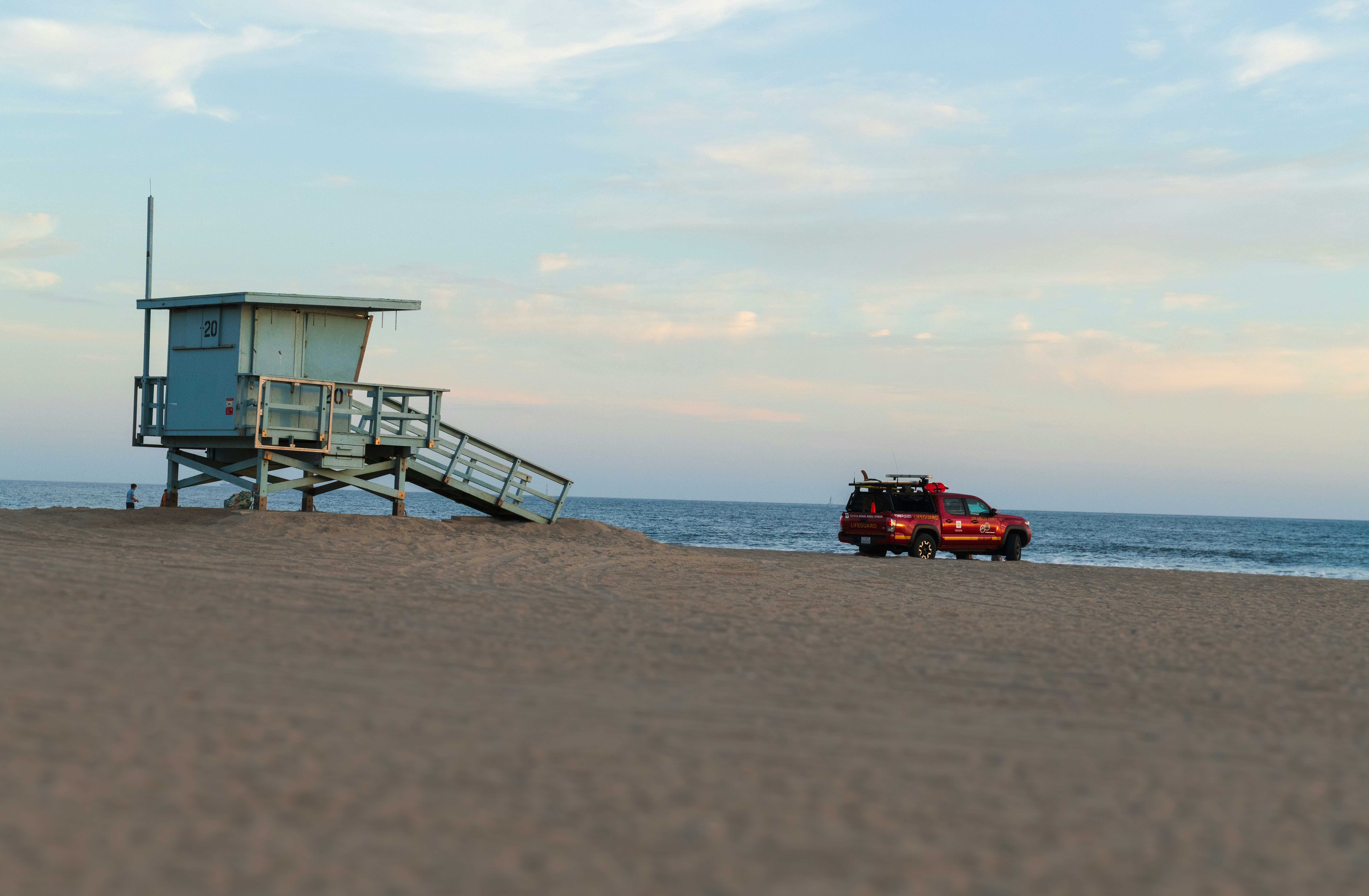 Lifeguard Station and Red SUV on Distant Shore