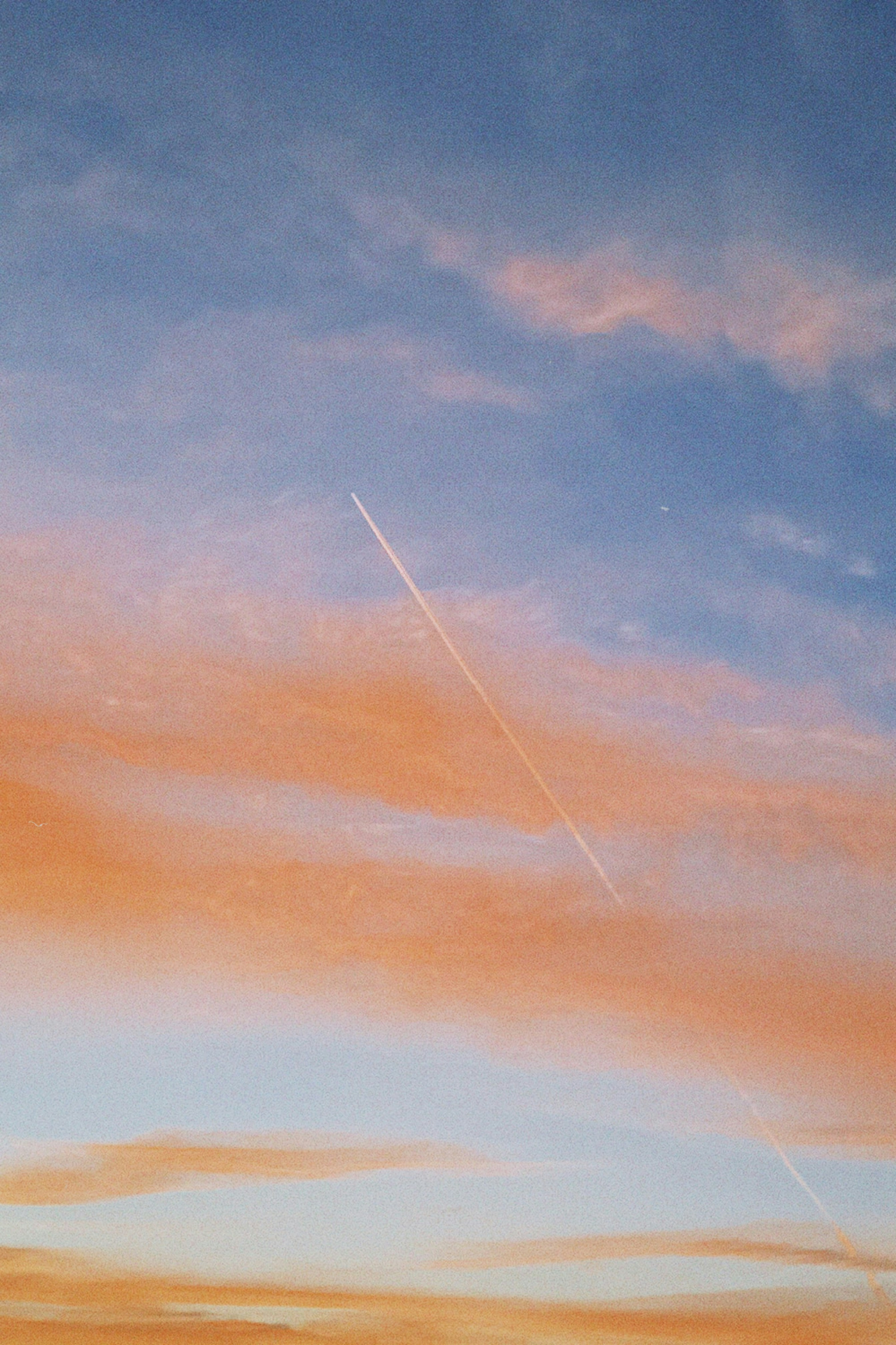 Contrail across a pastel sunset sky