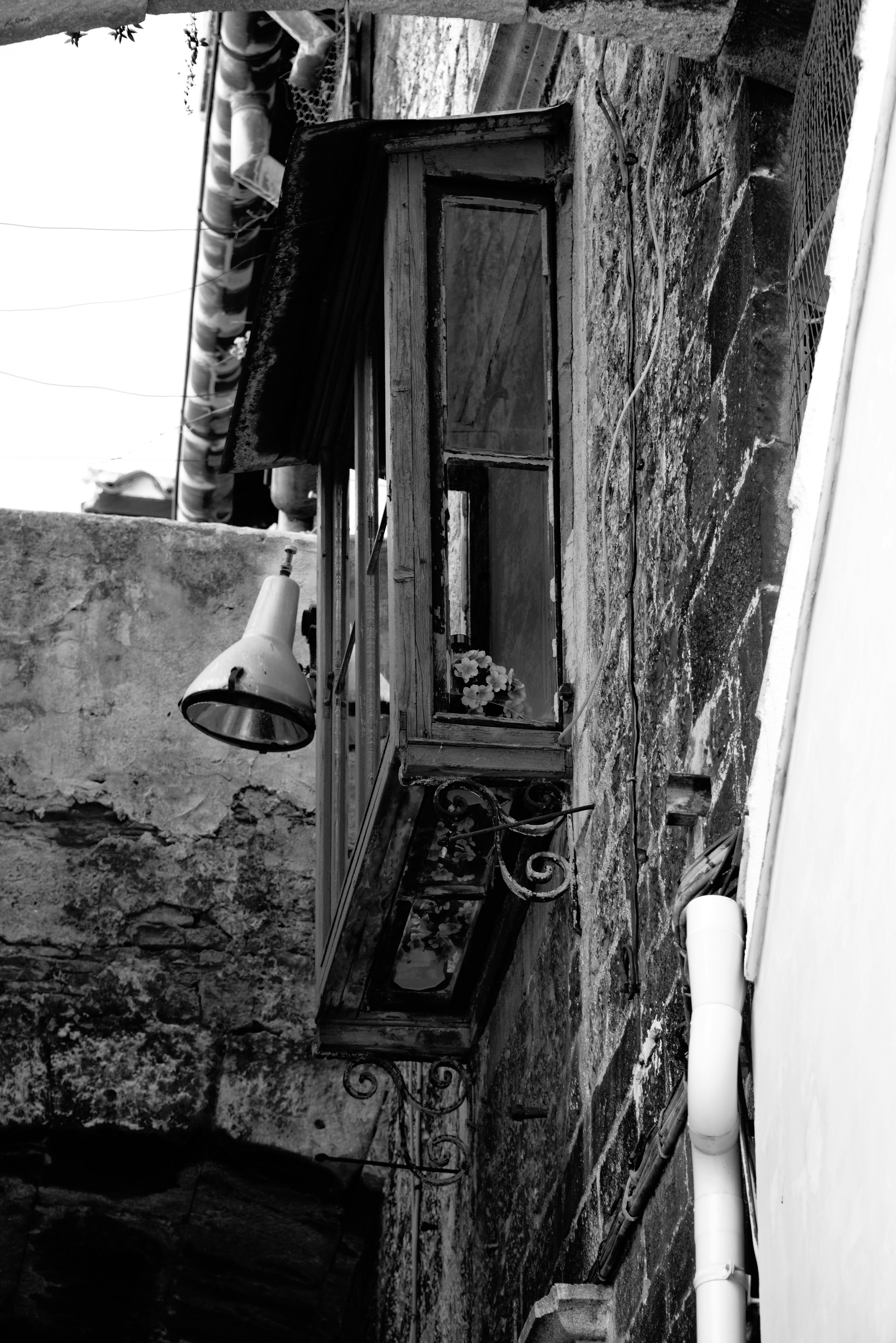 Weathered Balcony Lantern Casts a Quiet Frame on Stone Facade