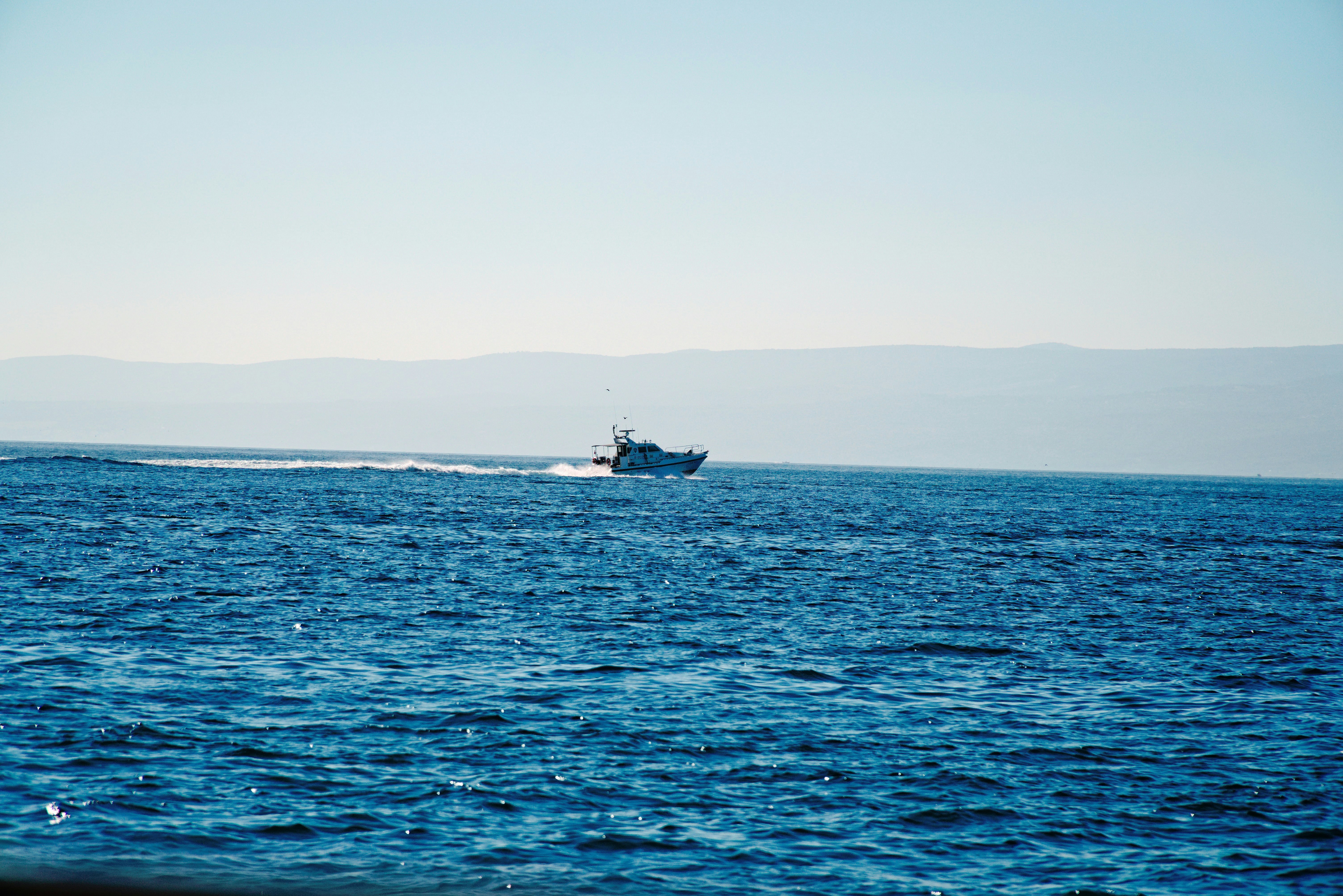Blue Horizon Vessel: A lone boat skims the distant sea