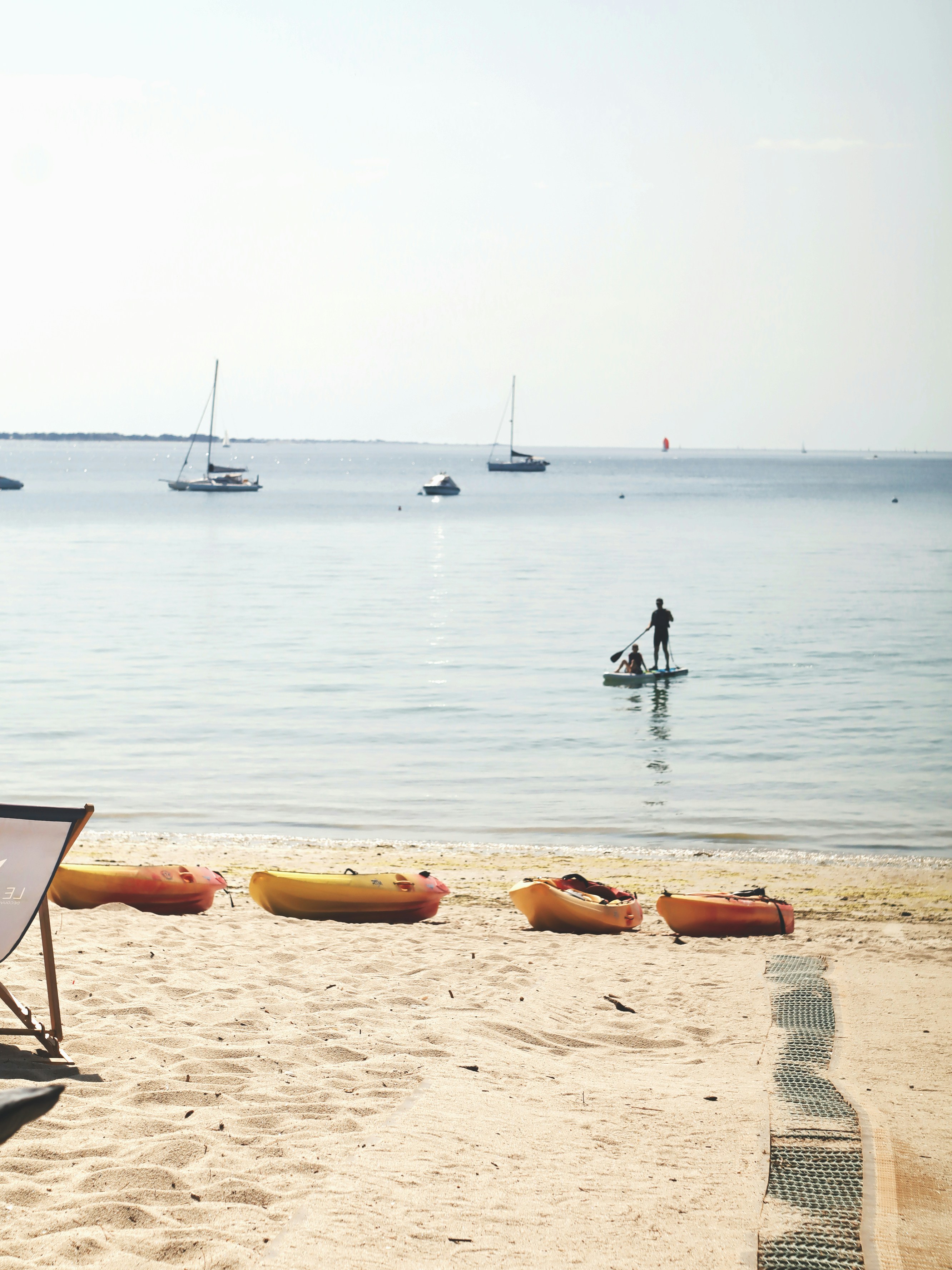 Gentle Sea at Dusk: Kayaker and Boats at Sunlit Shore