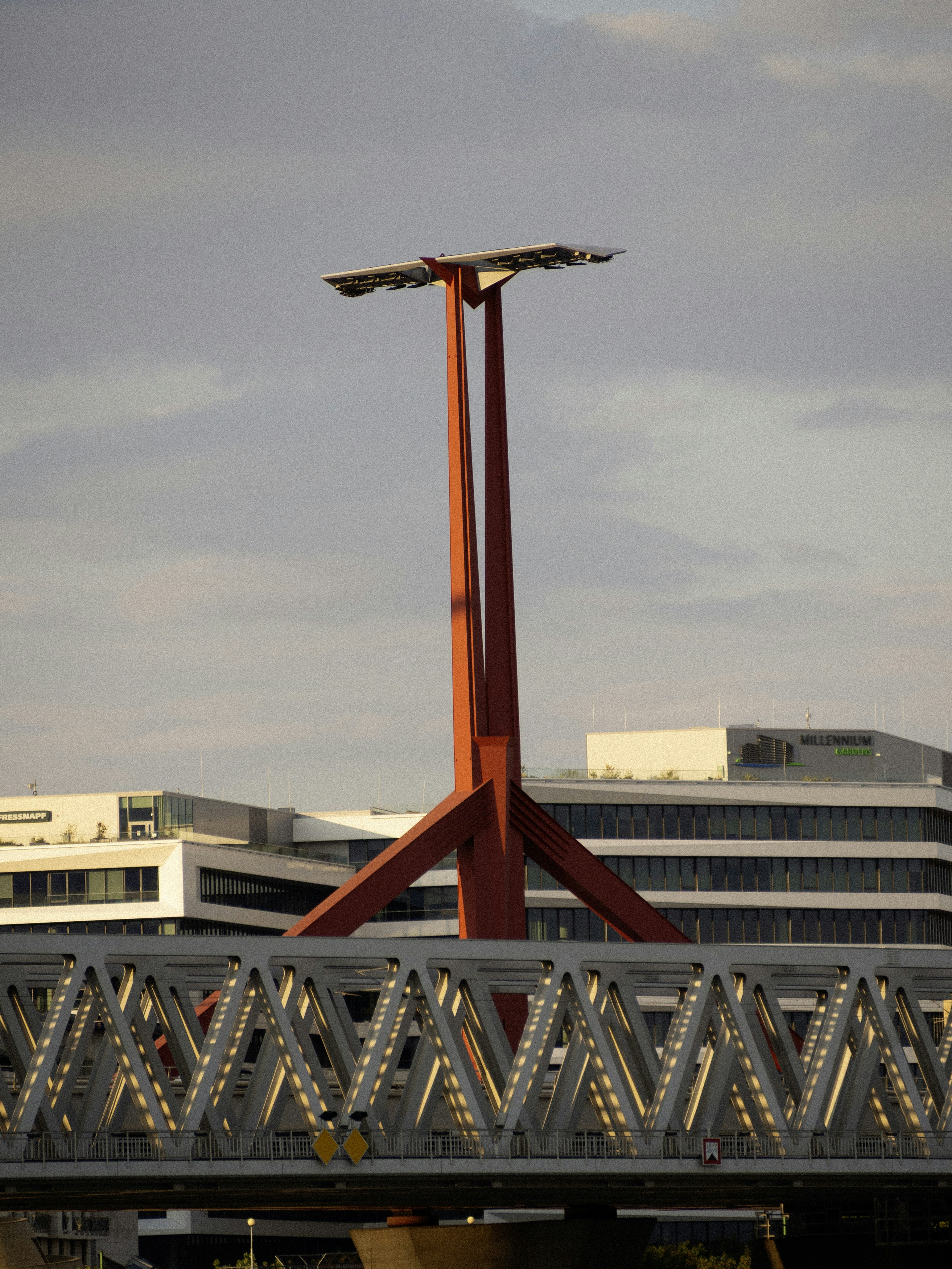 Red Skyline: The Vertical Tower Framing a City Bridge