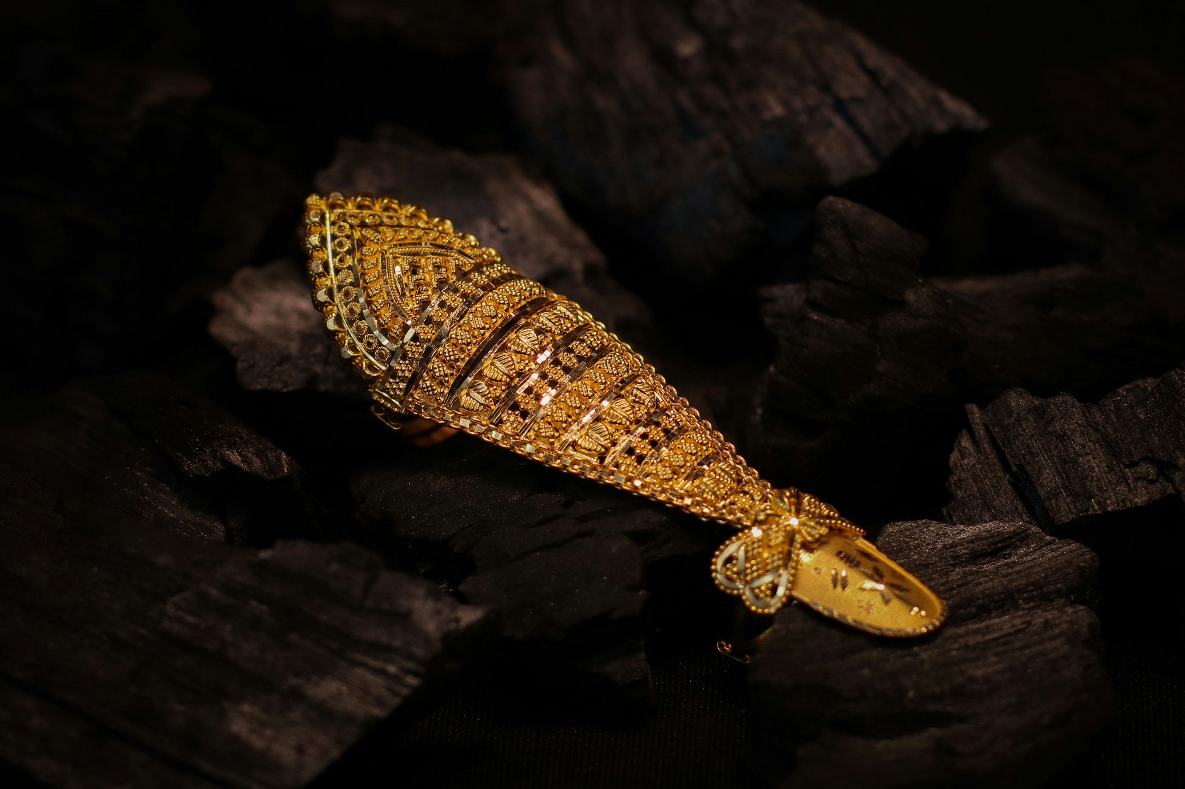 Golden pendant cocoon: a gleaming treasure resting on charcoal