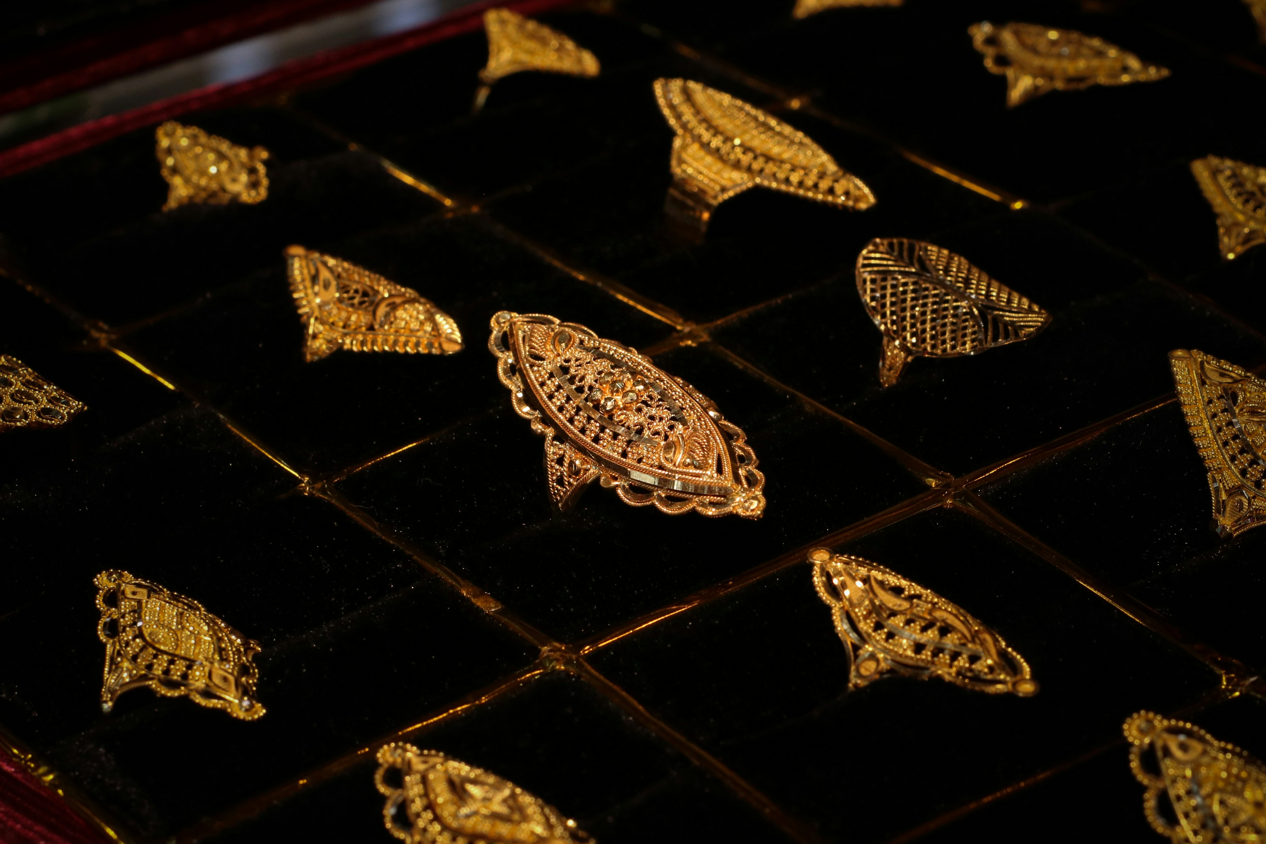 Gold filigree on a velvet grid: a jewelry collection under warm light