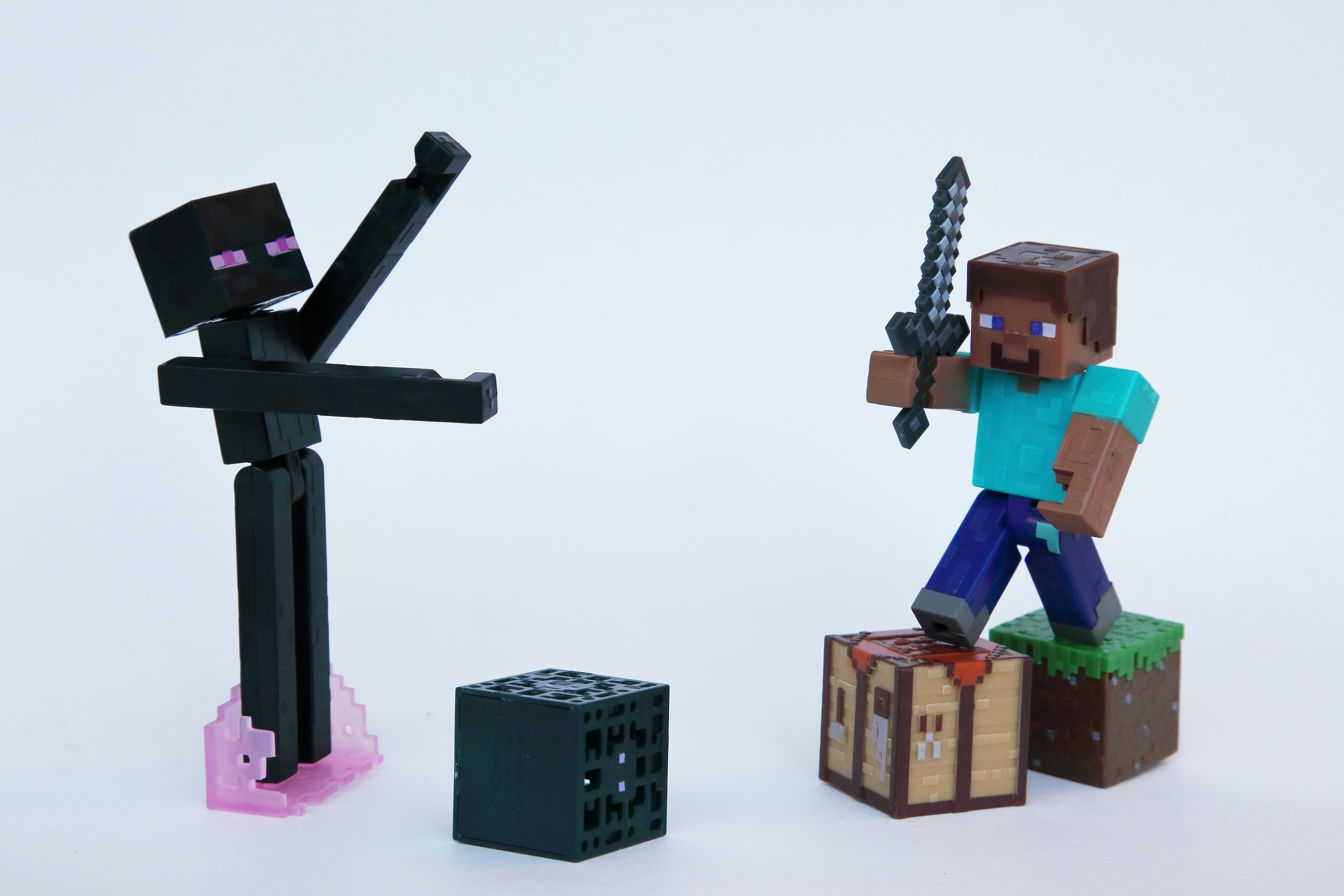 Two Minecraft-style minifigures face off with swords and props on a plain white background; a black creeper cube and a crafting chest complete the scene.