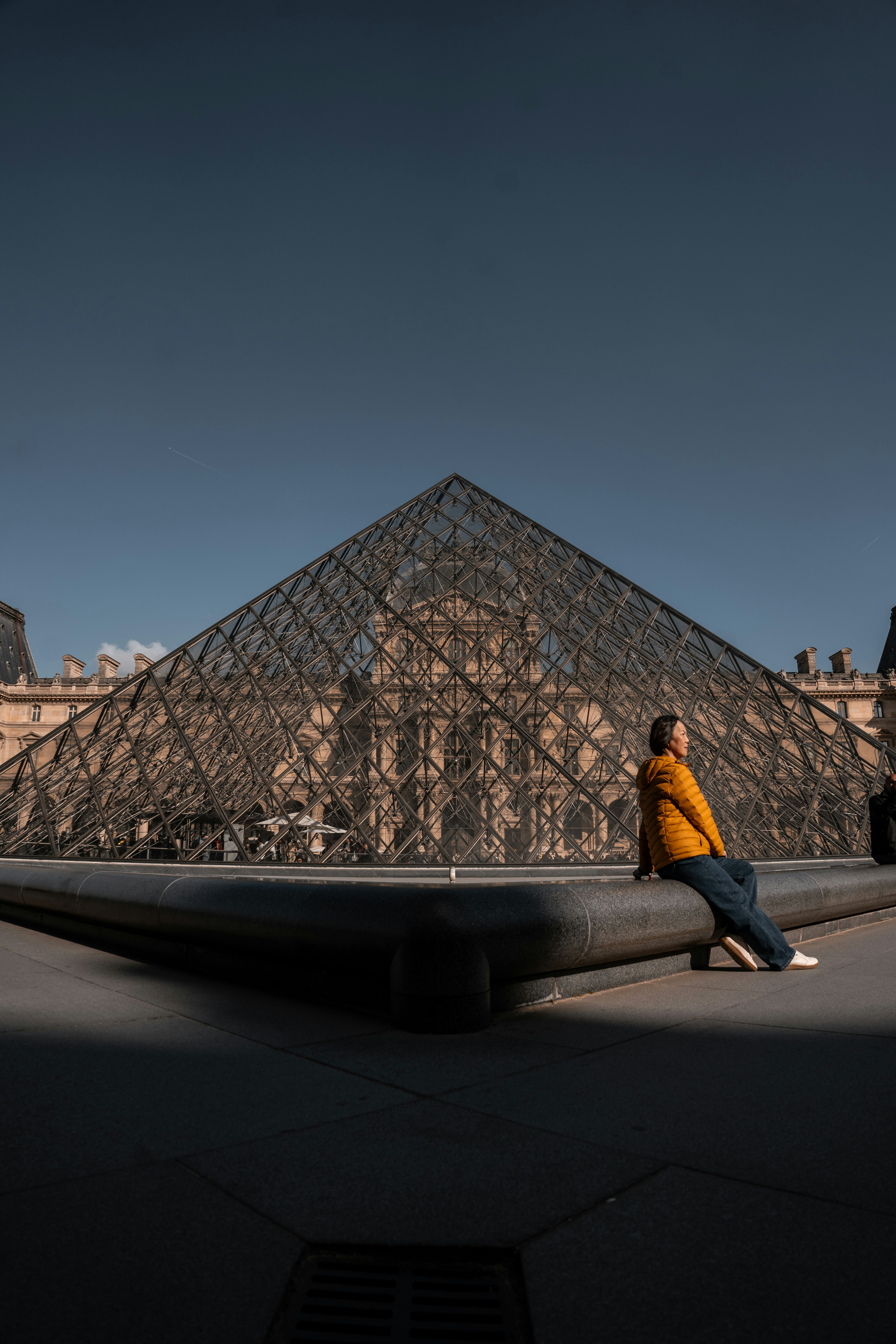 Solitary traveler by the Louvre pyramid at golden hour