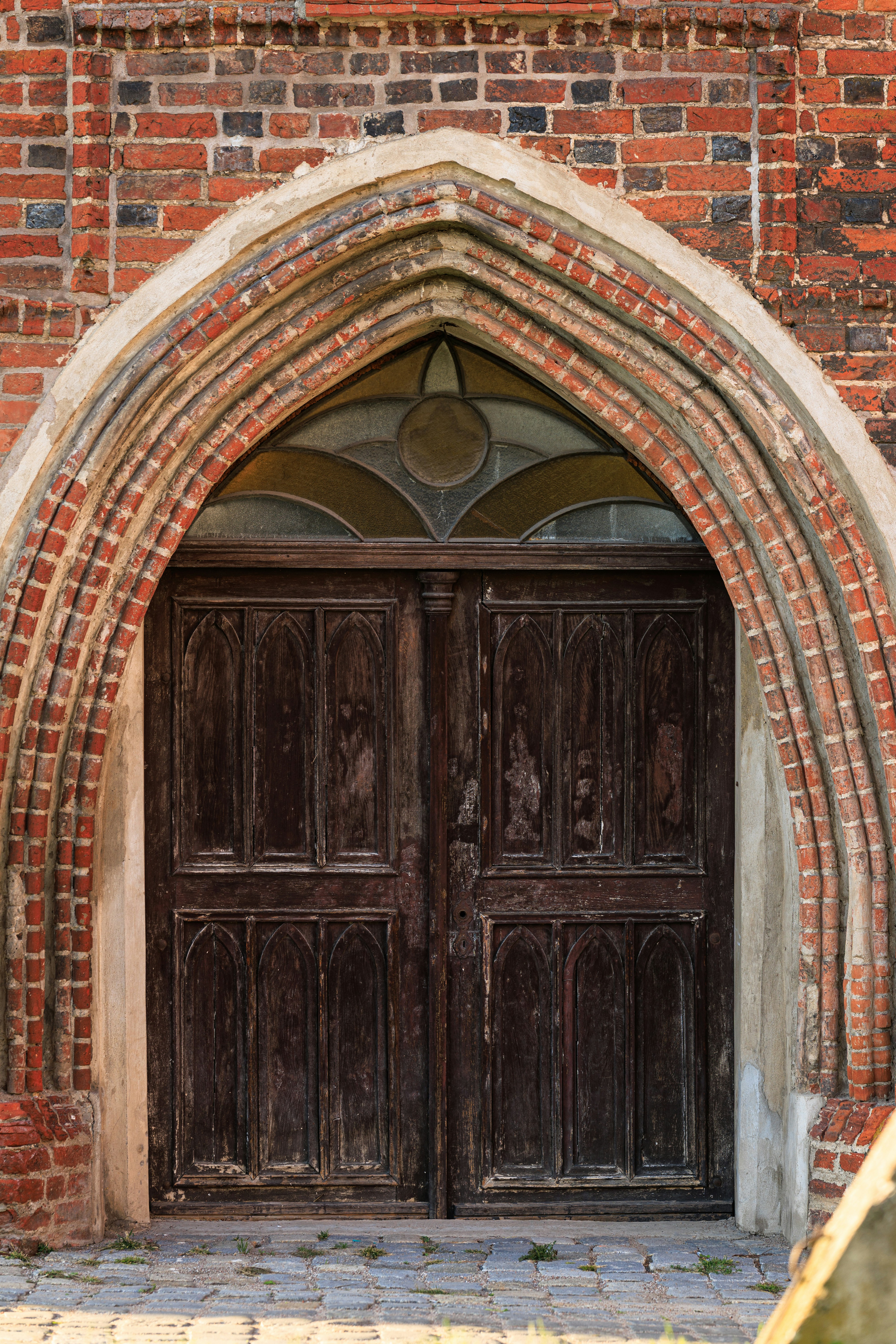 Dark Wooden Doors Beneath a Brick Archway