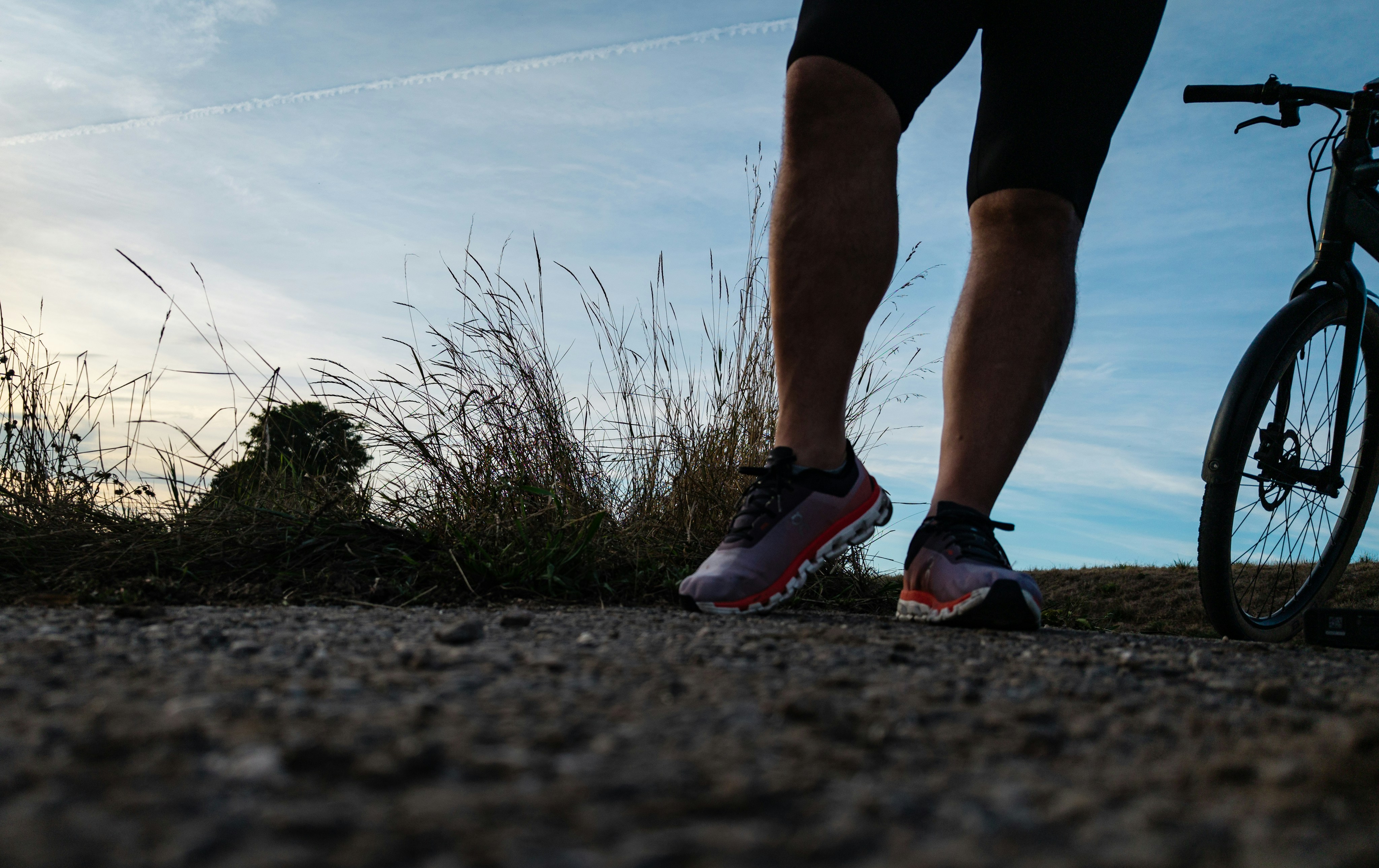 Close-quarters stride: feet and bicycle edge in a post-sunset ride