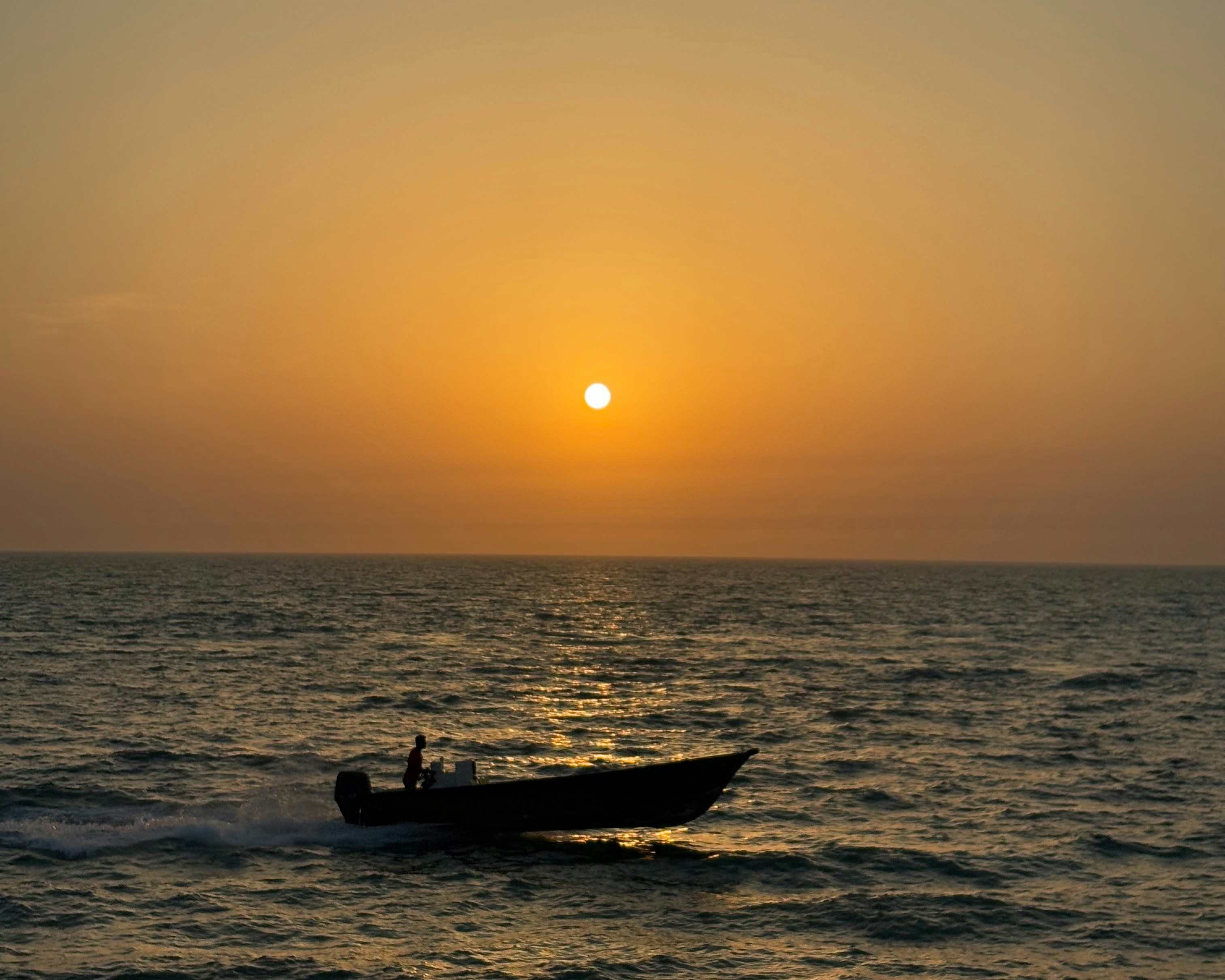 Sunlit Horizon: Boat Silhouette at Dusk